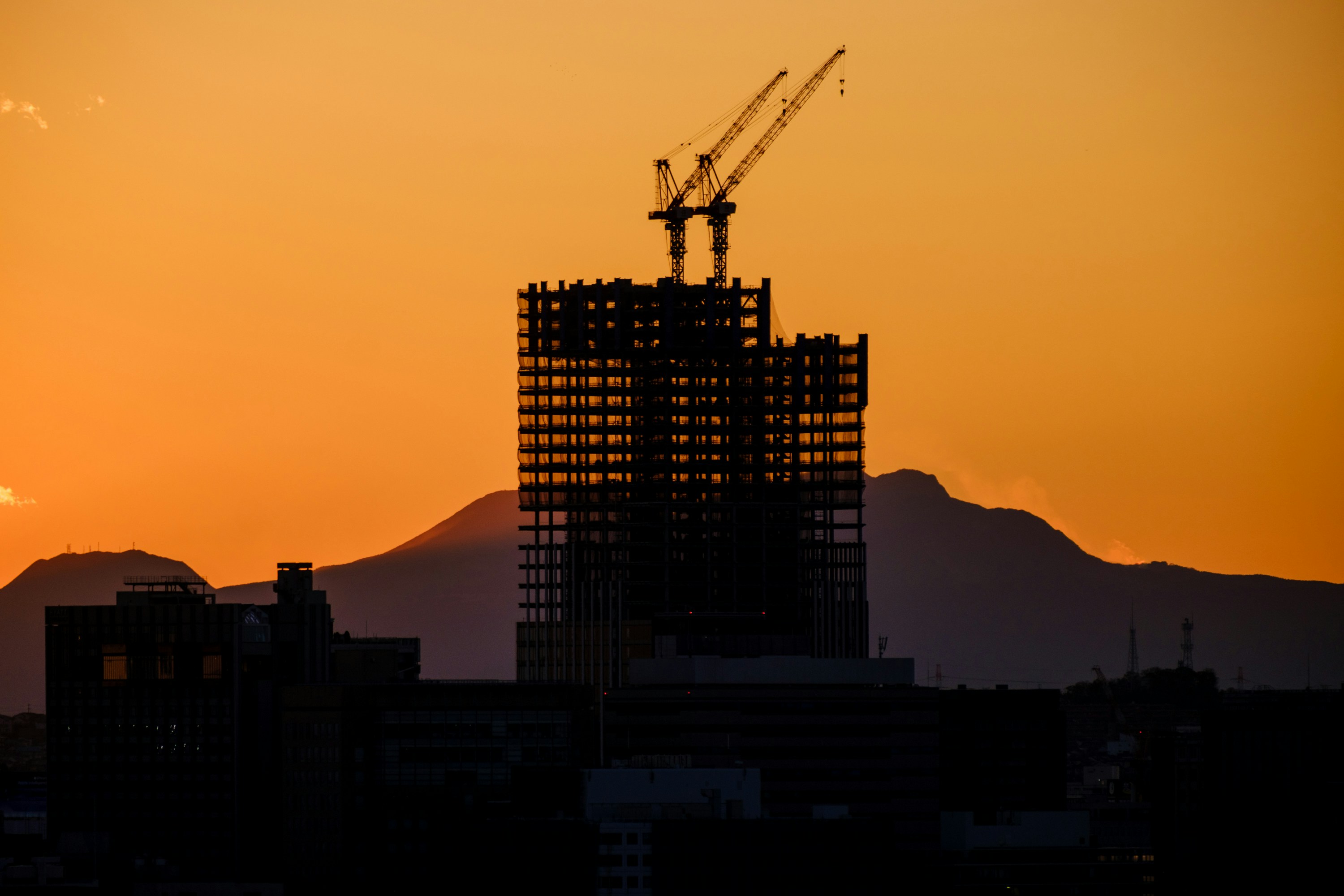 A building under construction with the sun setting in the background ...