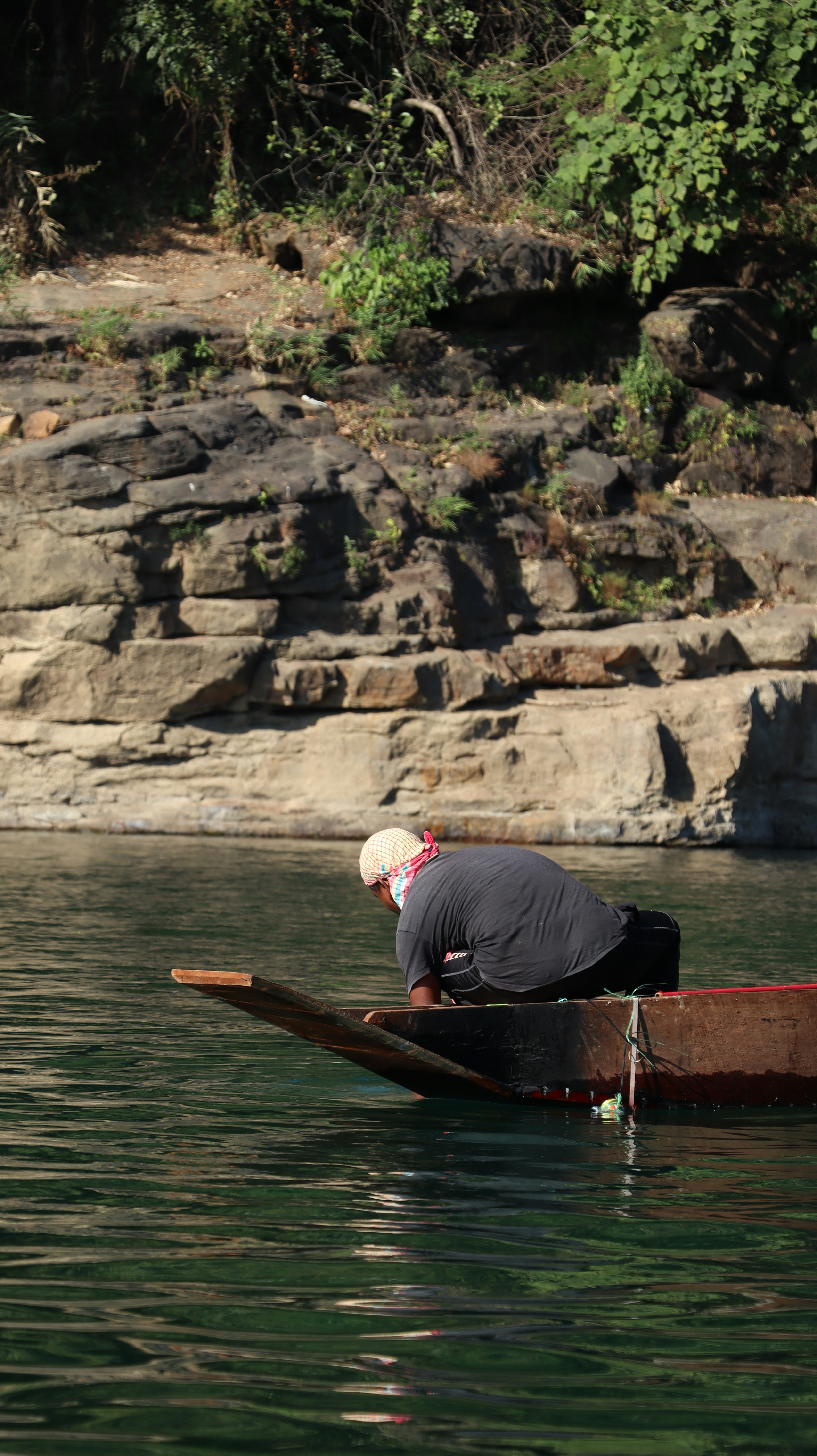 Calm River Work: A Figure in a Craft Amidst Stone and Greenery