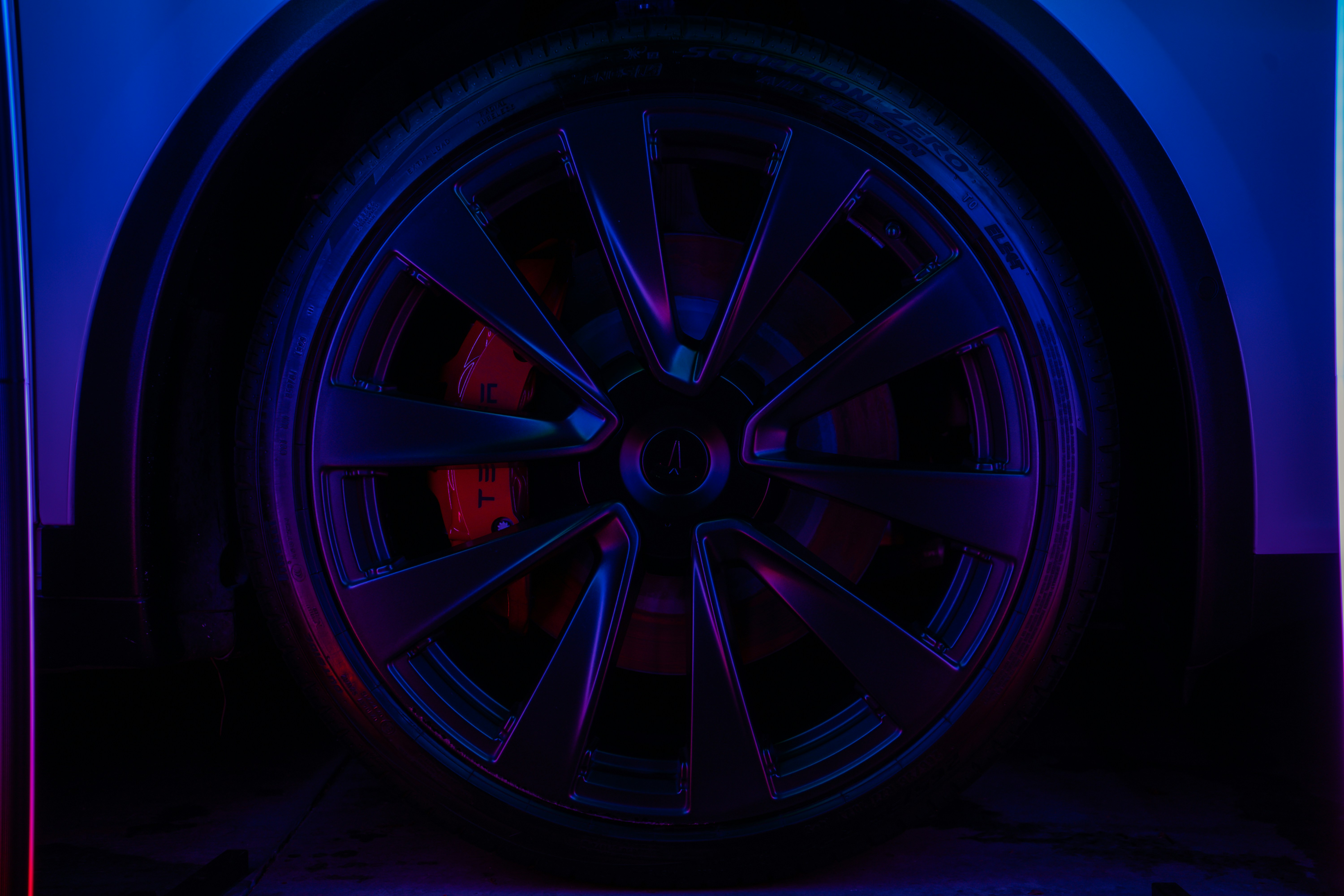 Neon-Toned Rim in Blue-Violet Night: A Close-Up of the Car Wheel