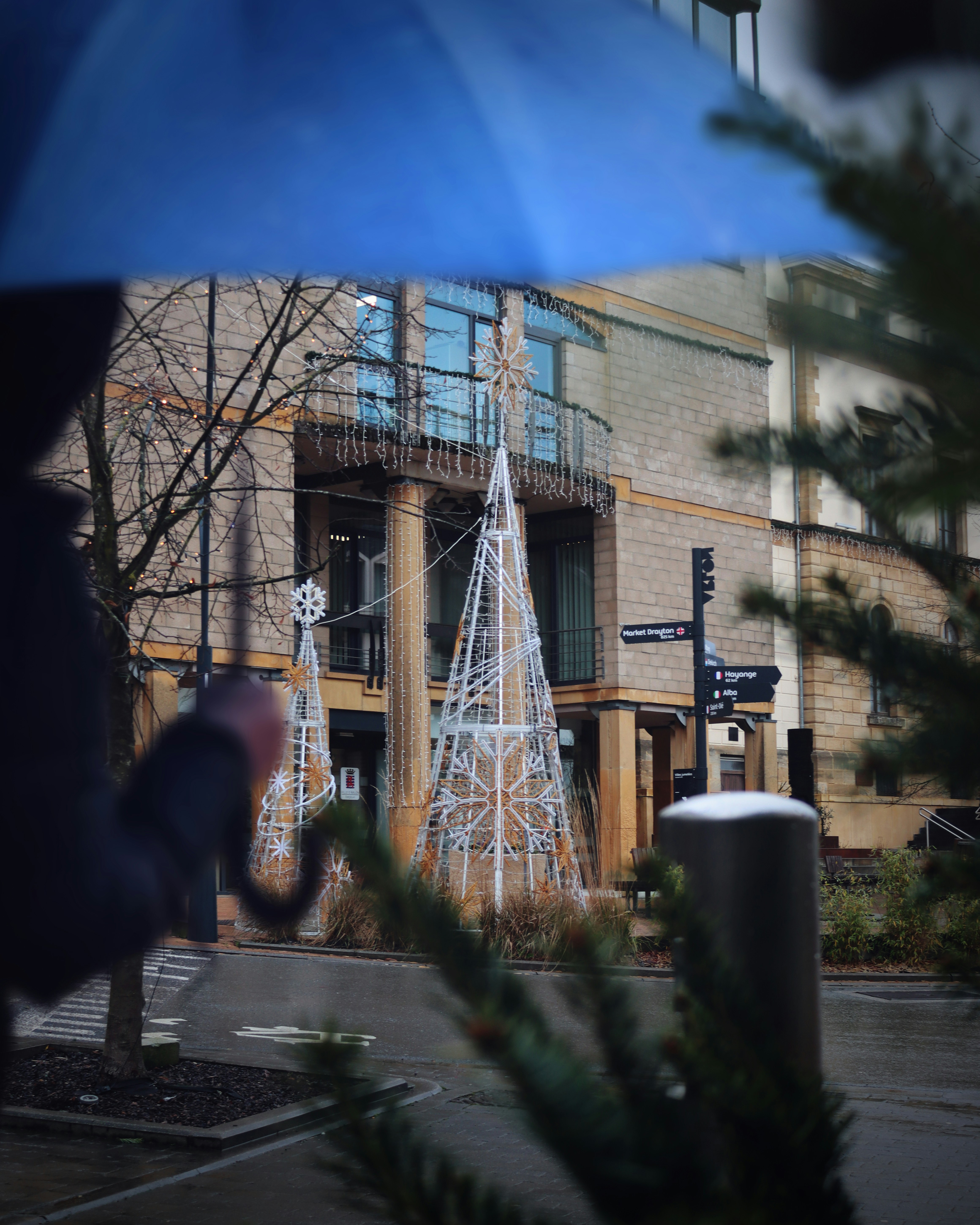 Snowlit Christmas Tree Sculpture Framed by an Umbrella and Urban Facade