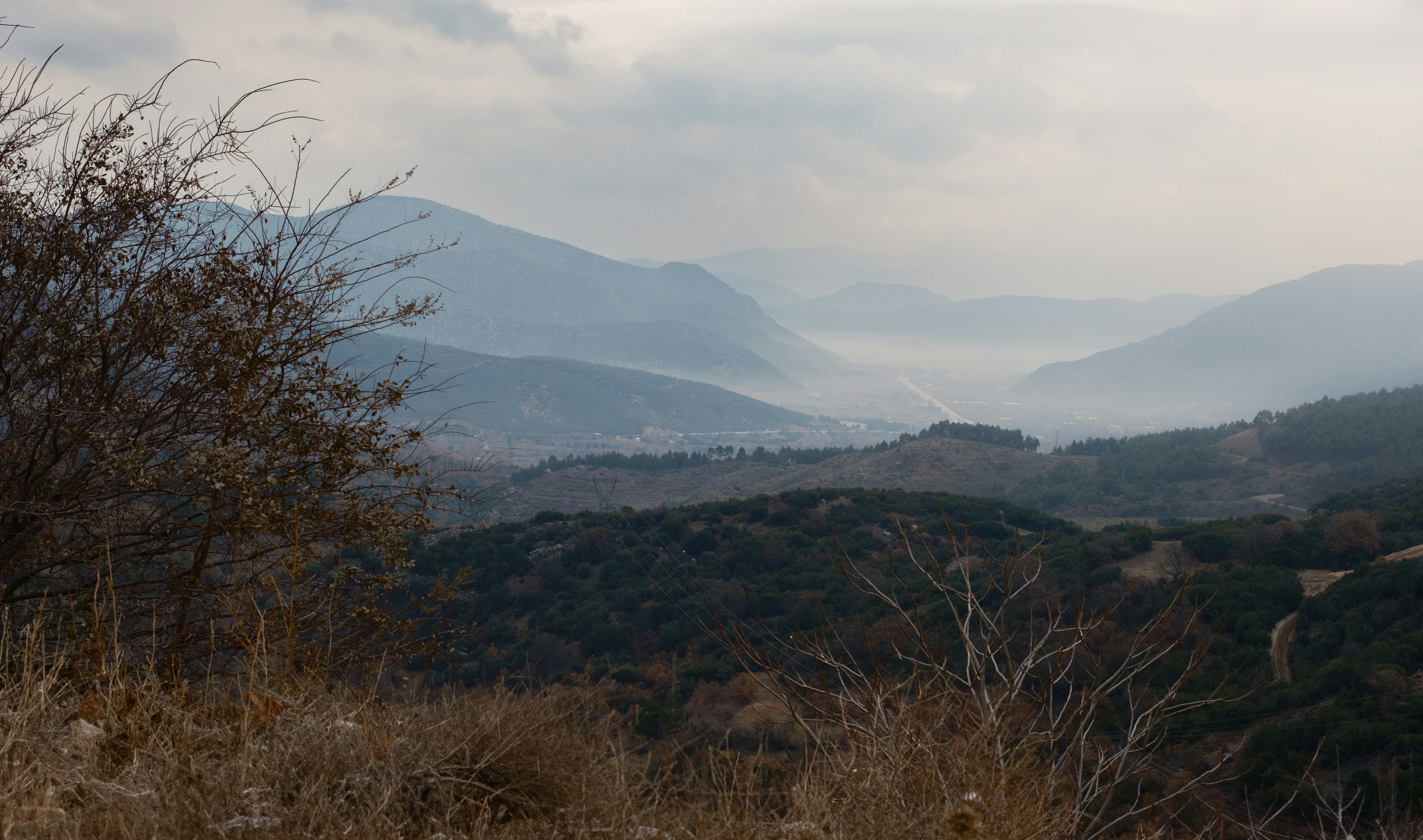 Rolling hills and distant mountains shrouded in mist under a cloudy sky.