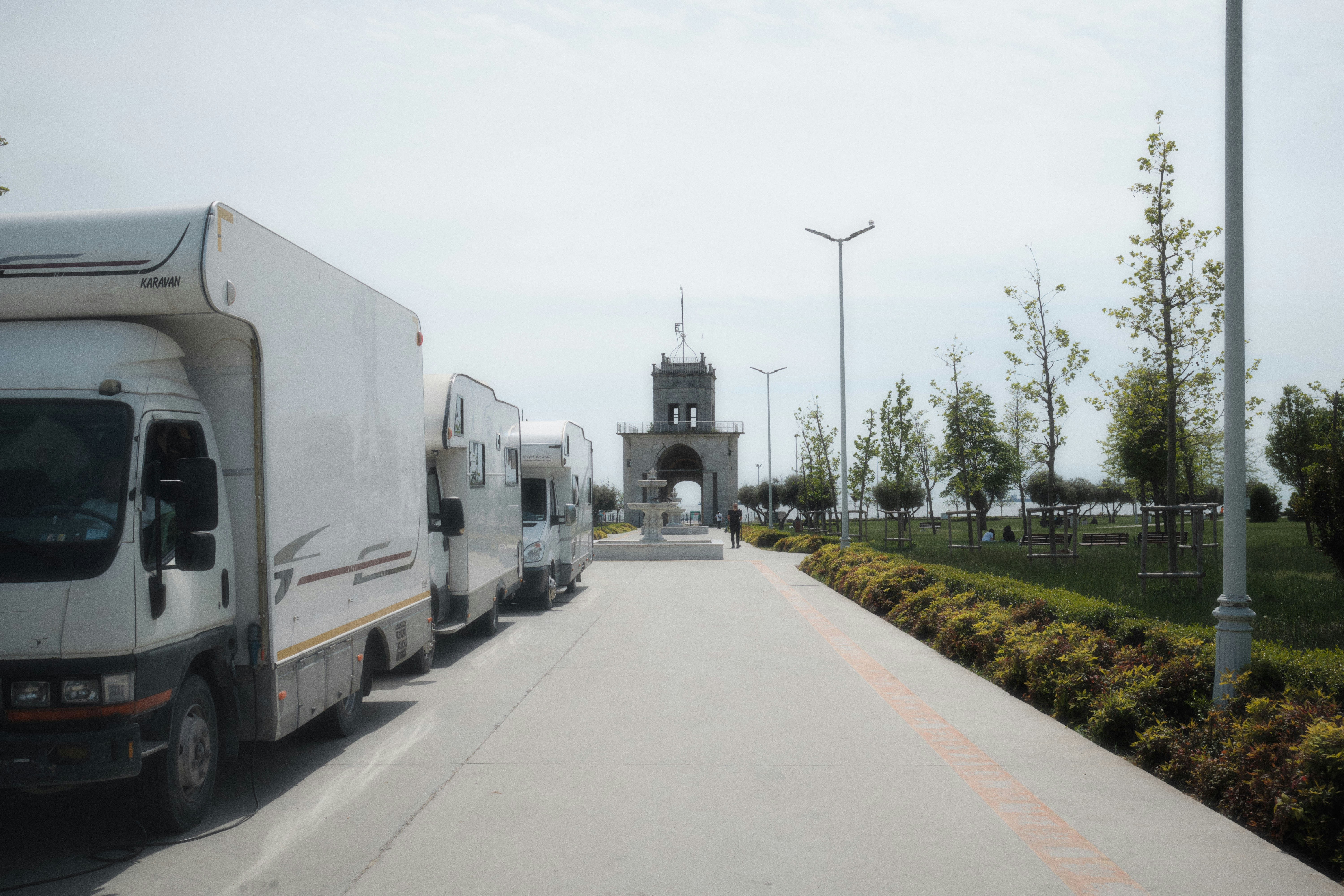 Left-Lined Trucks Meet a Distant Arch: A Quiet Boulevard Toward History