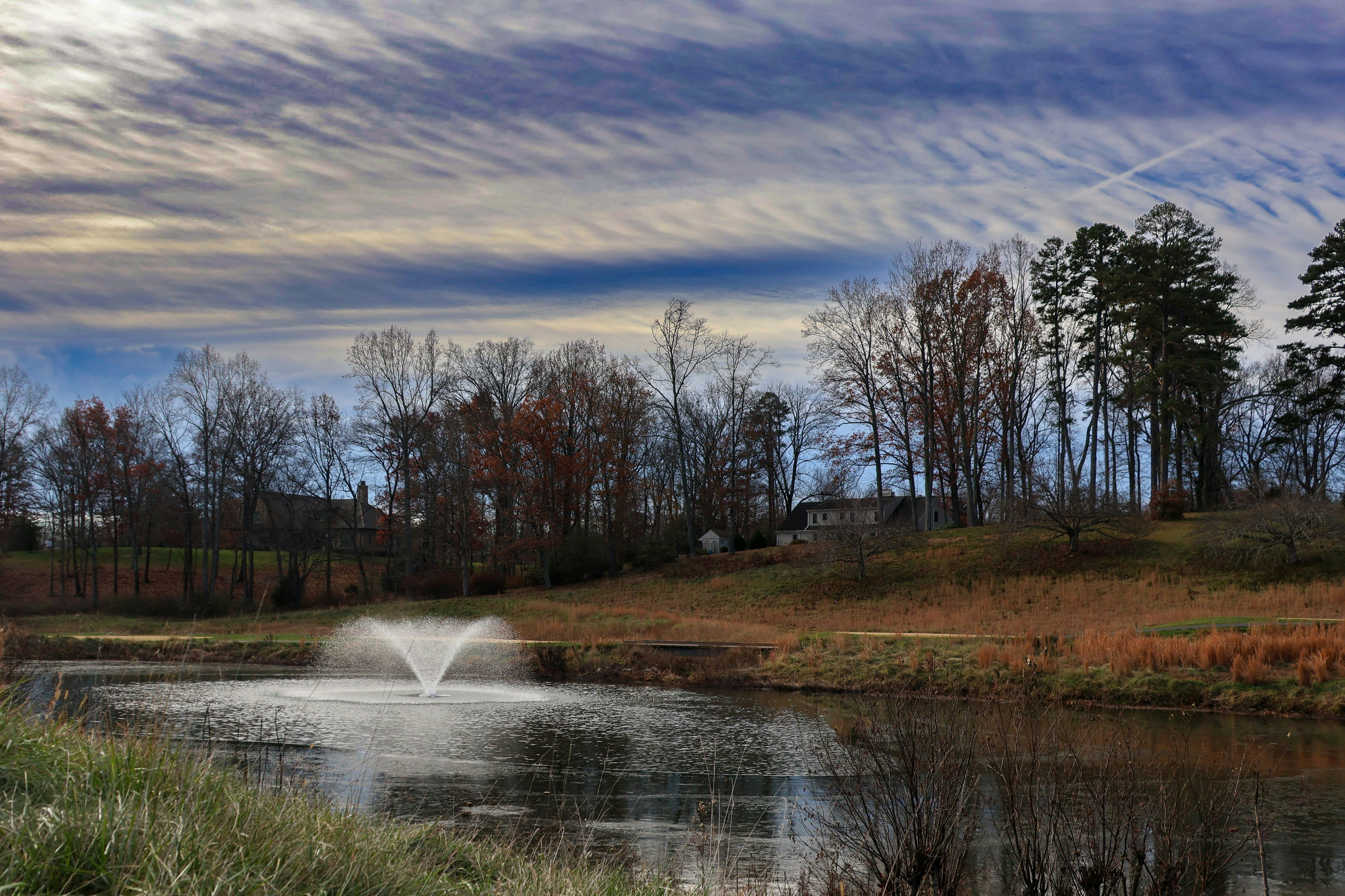 Whispering Fountain on an Autumn Pond under a Layered Sky