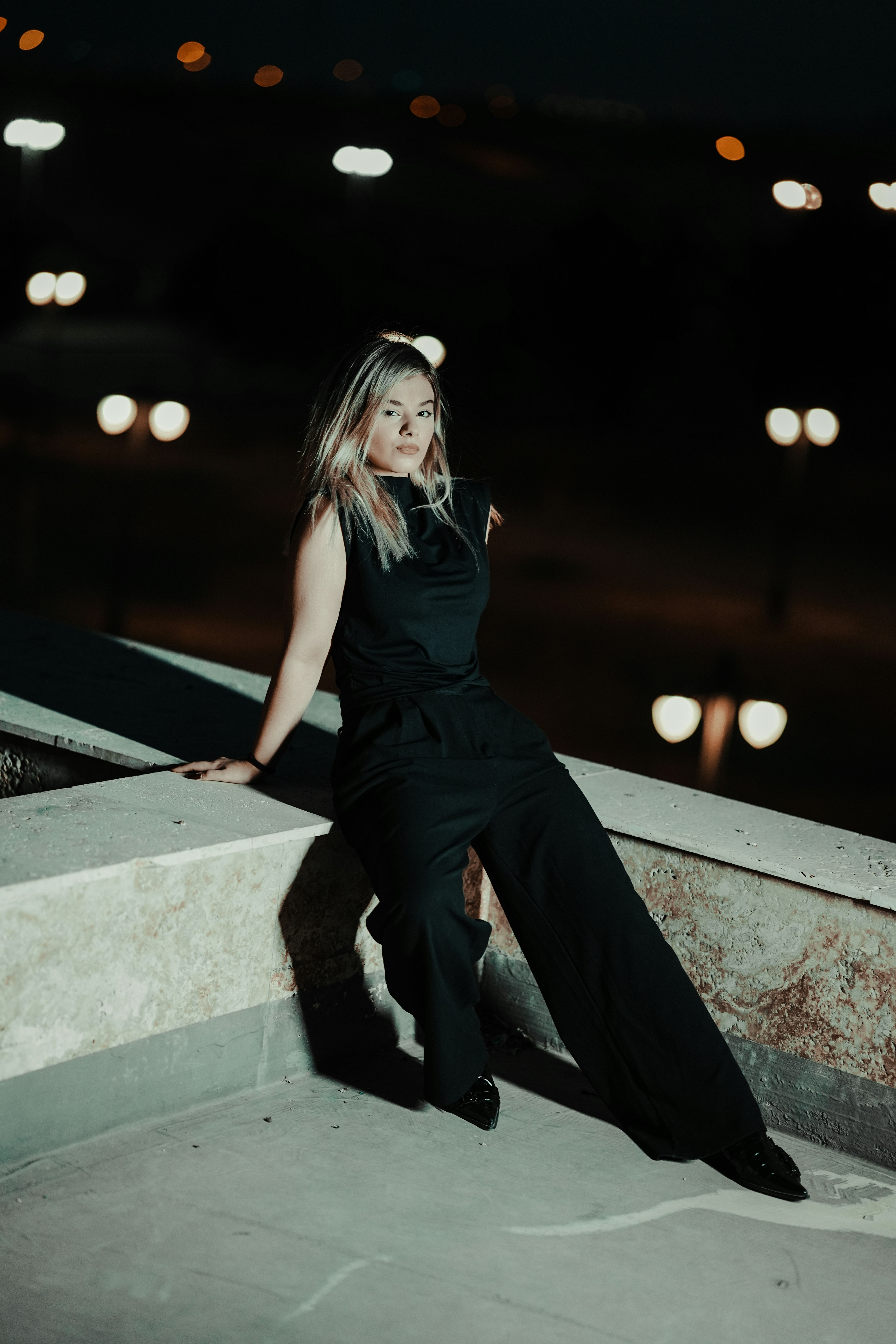 A woman in a black dress sitting on a ledge photo – Free Formal wear ...