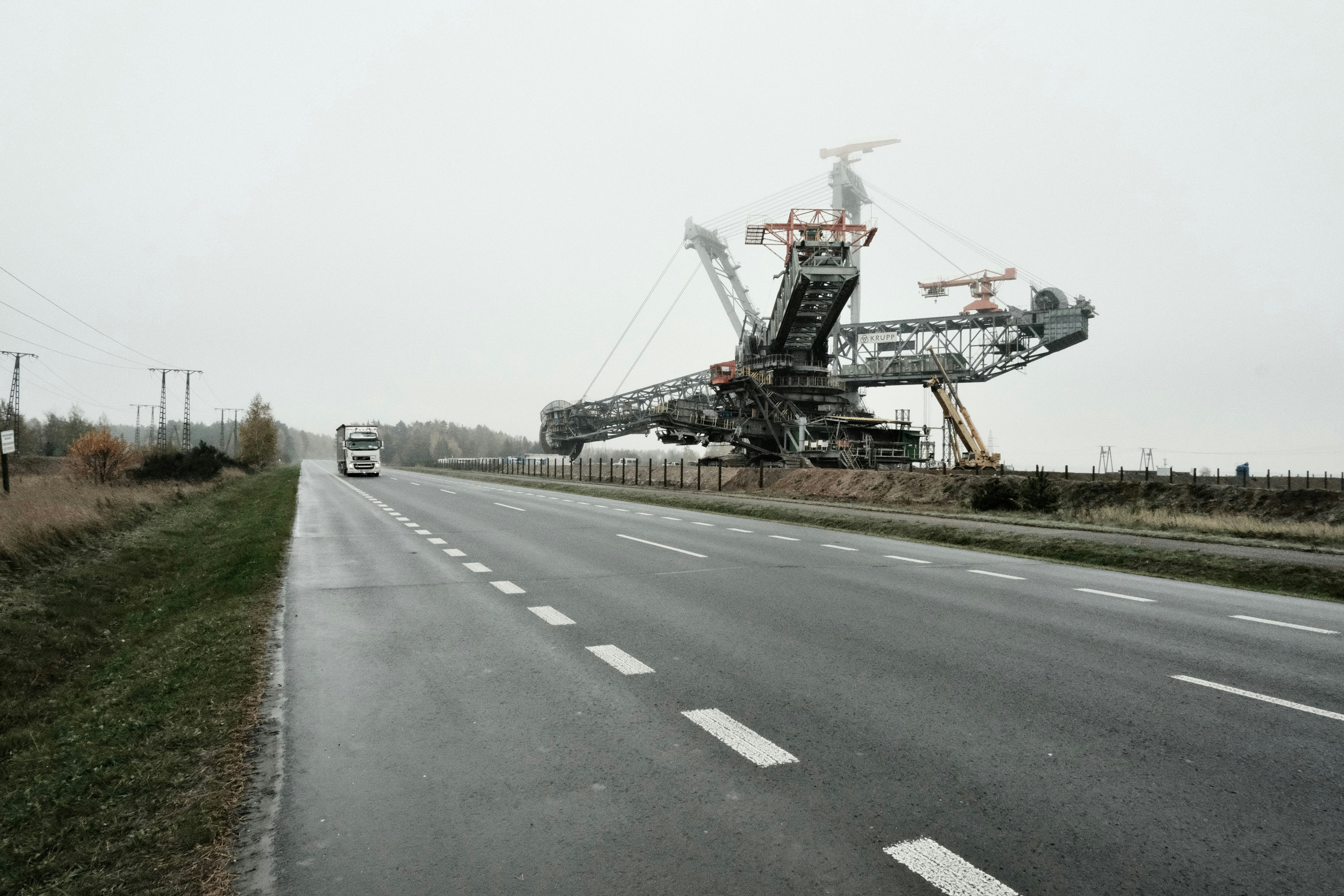 Dragline at the Verge: A Monolithic Crane Looms Over an Empty Highway