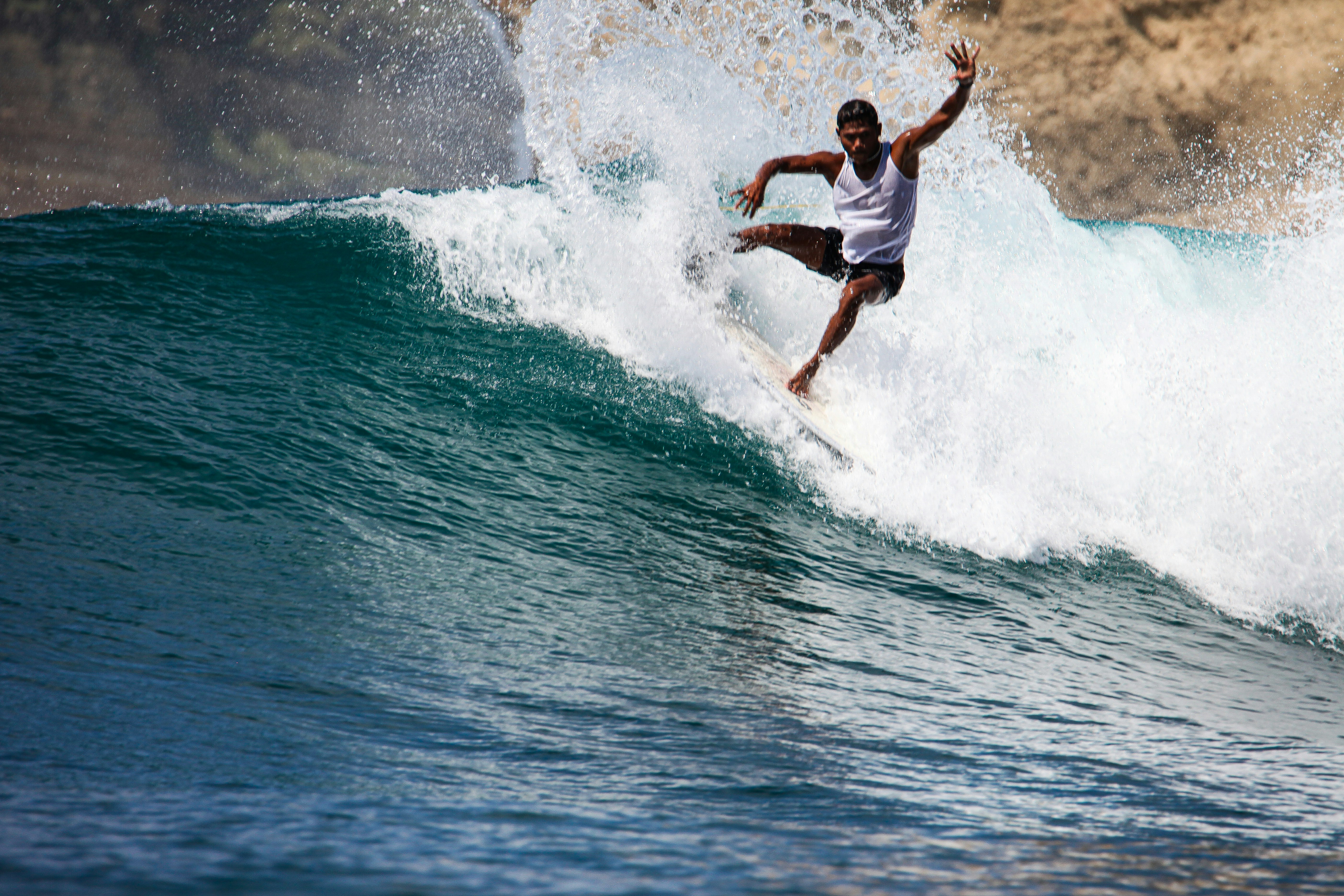 Rider carving a curling turquoise lip under a spray‑soaked crest