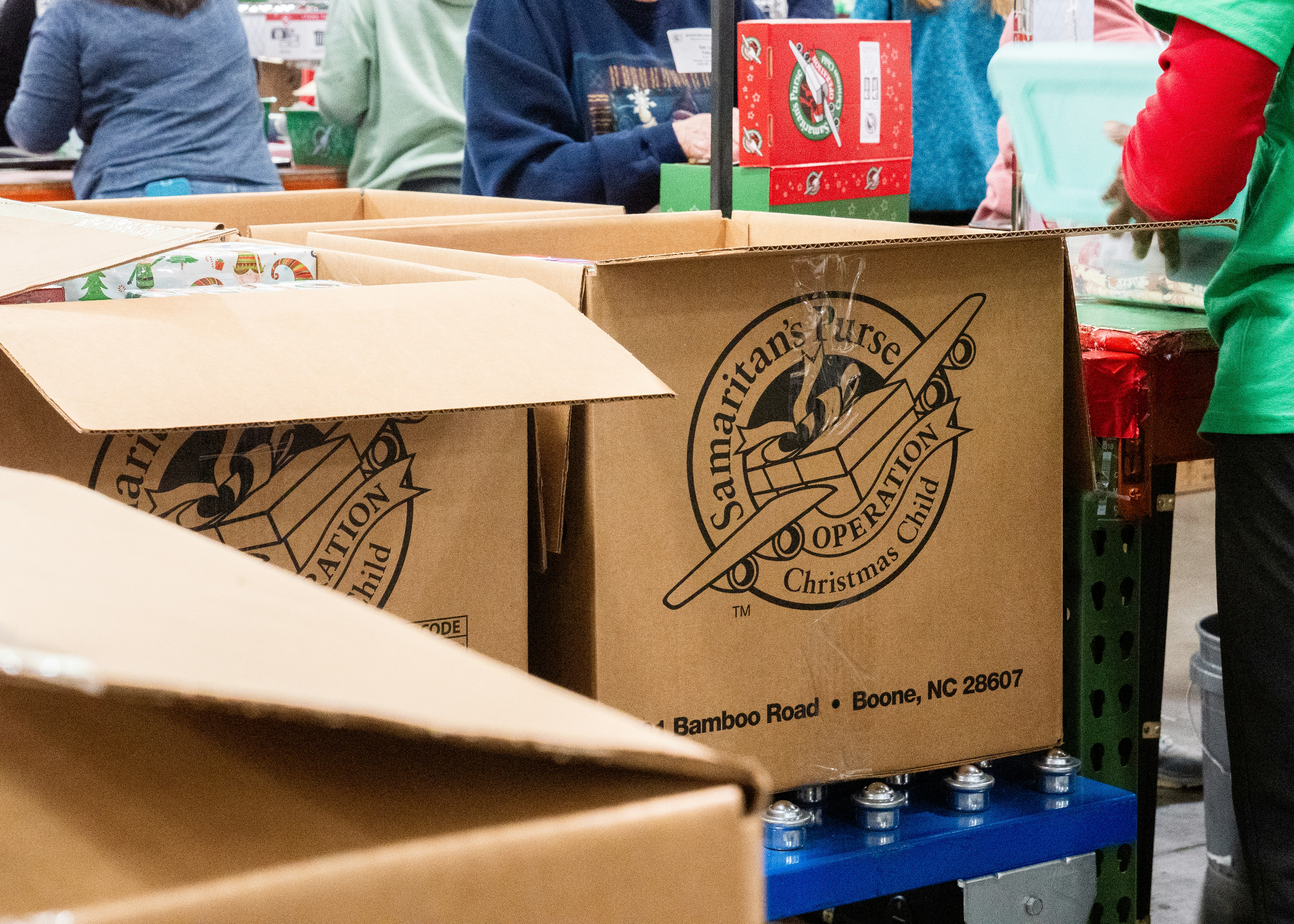 A group of people standing around boxes in a store photo – Free ...