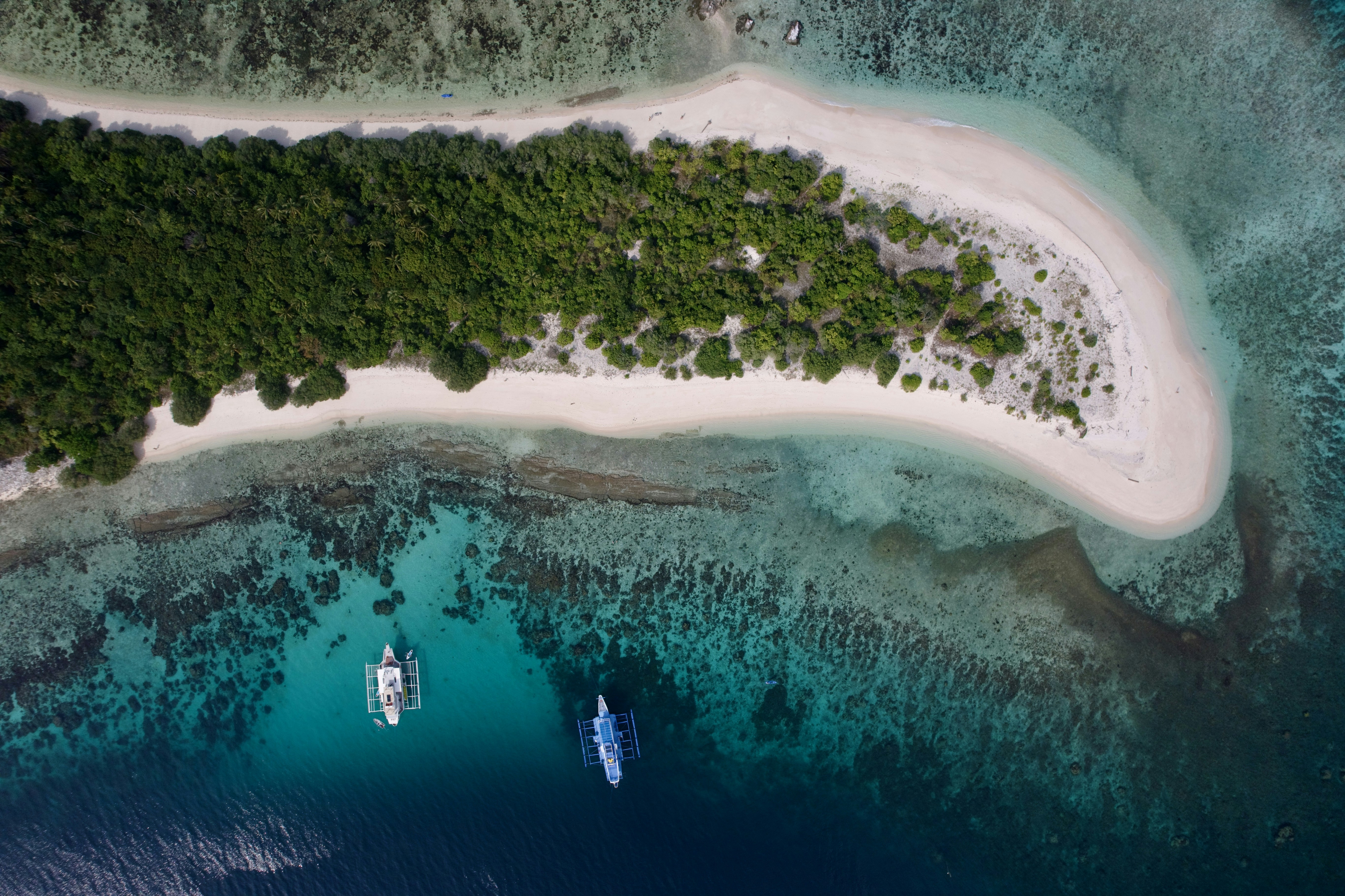 An aerial view of two boats in the water near an island photo – Free ...