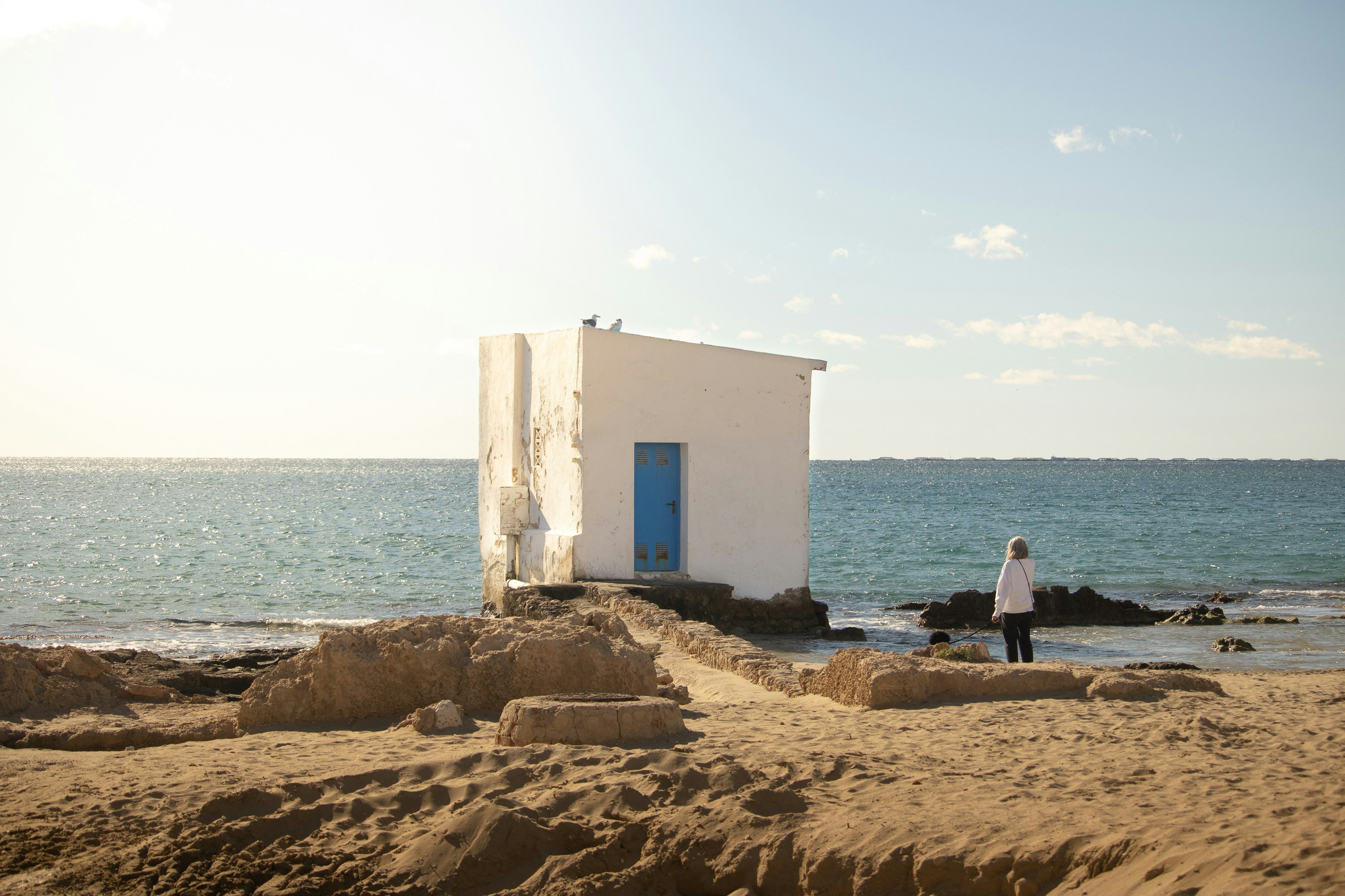 A small white building sitting on top of a sandy beach photo – Free ...