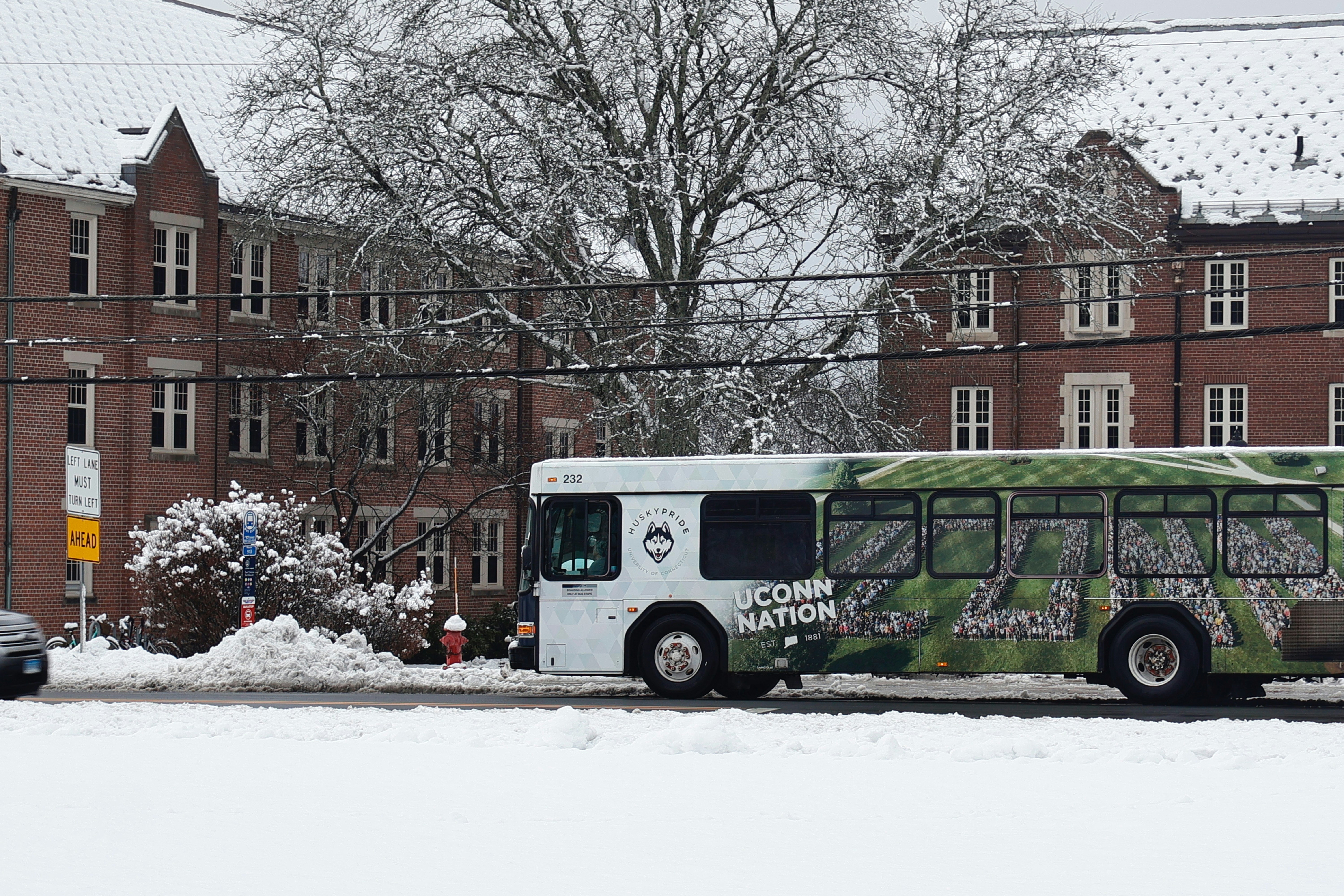 Green Bus on a Snow-Covered Campus: Modern Transit Amid Brick Façades