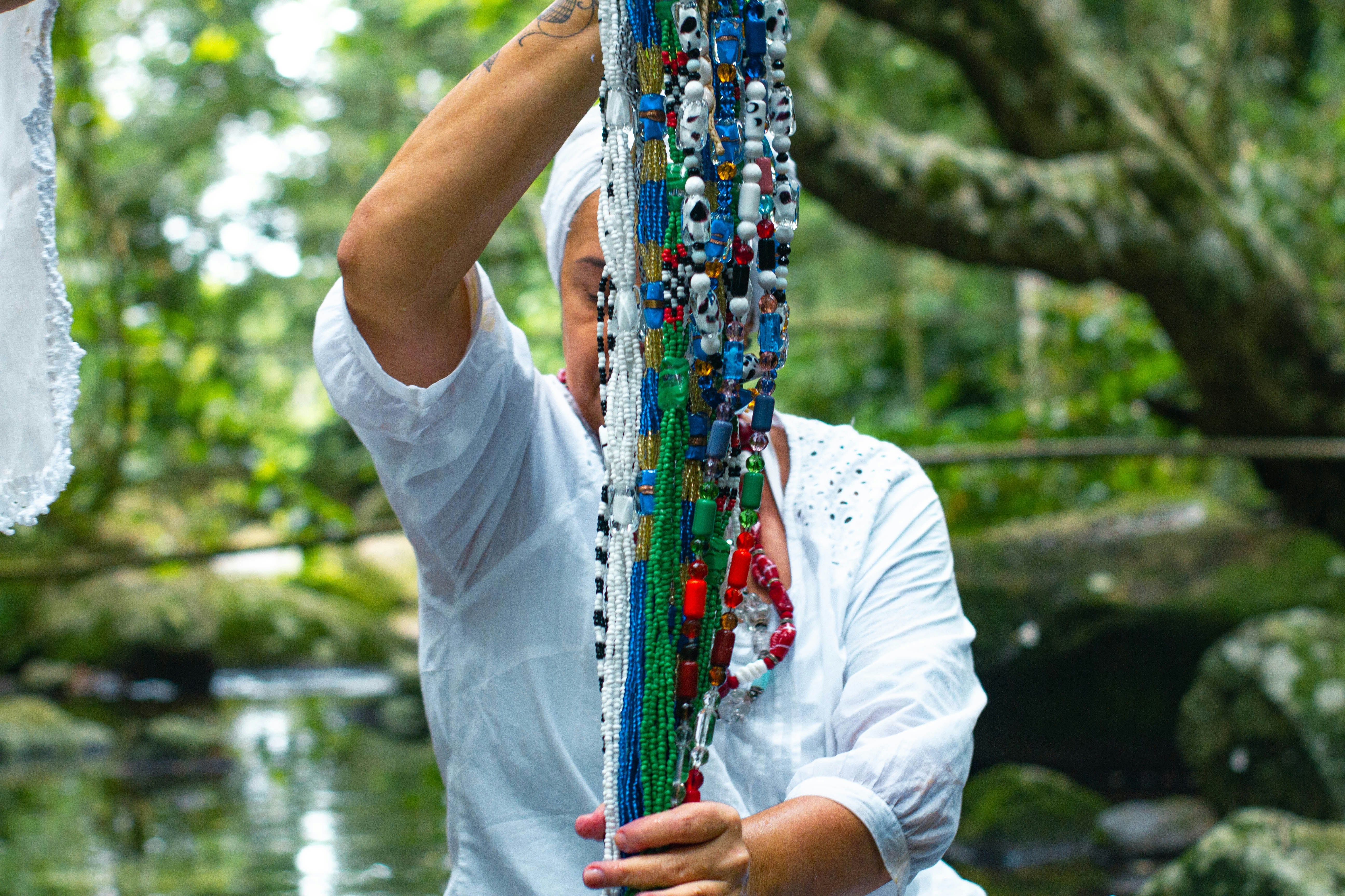 Person holding a colorful beaded item in a verdant forest setting.