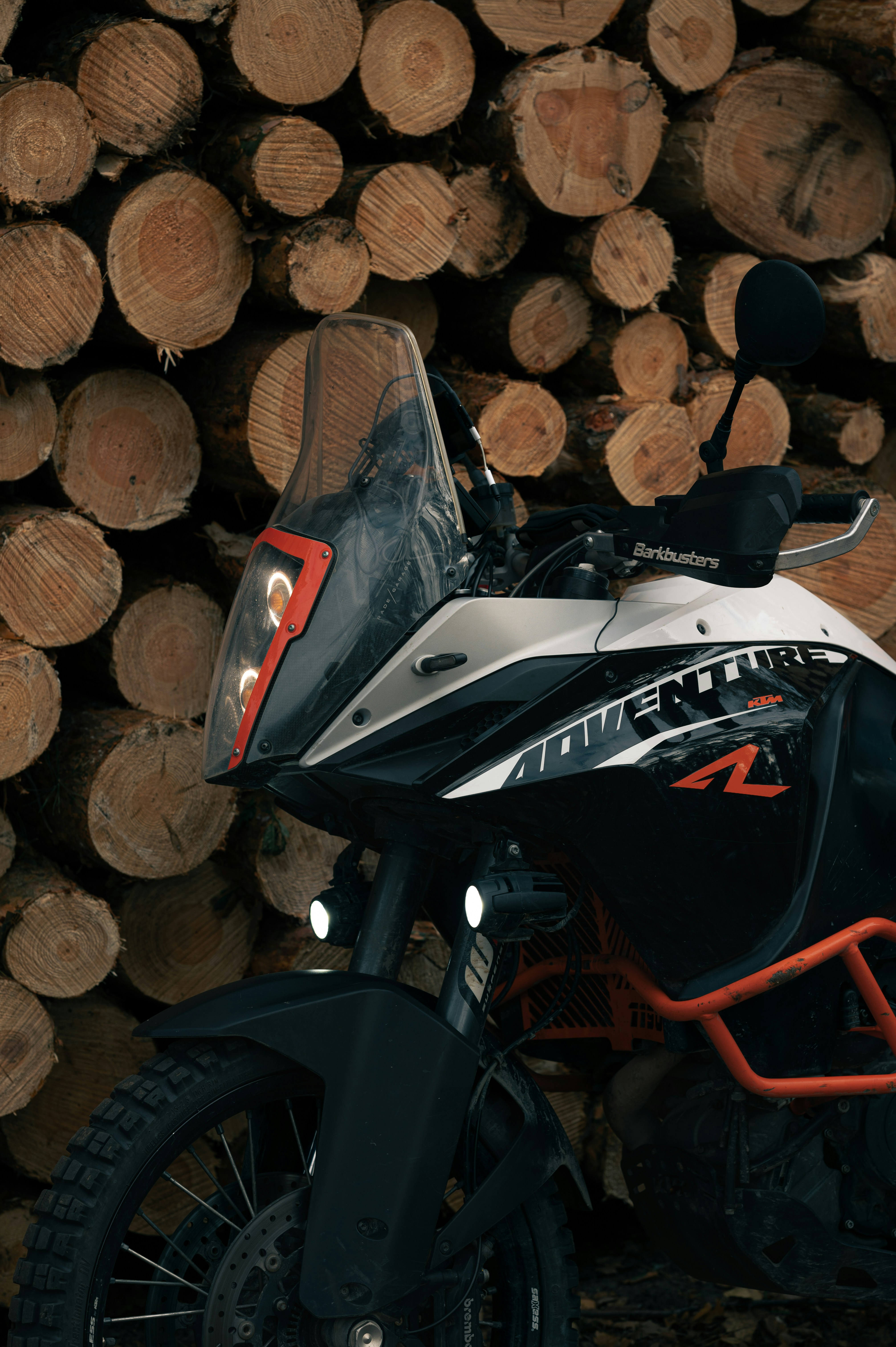 A motorcycle parked next to a pile of logs photo – Free Motorcycle ...