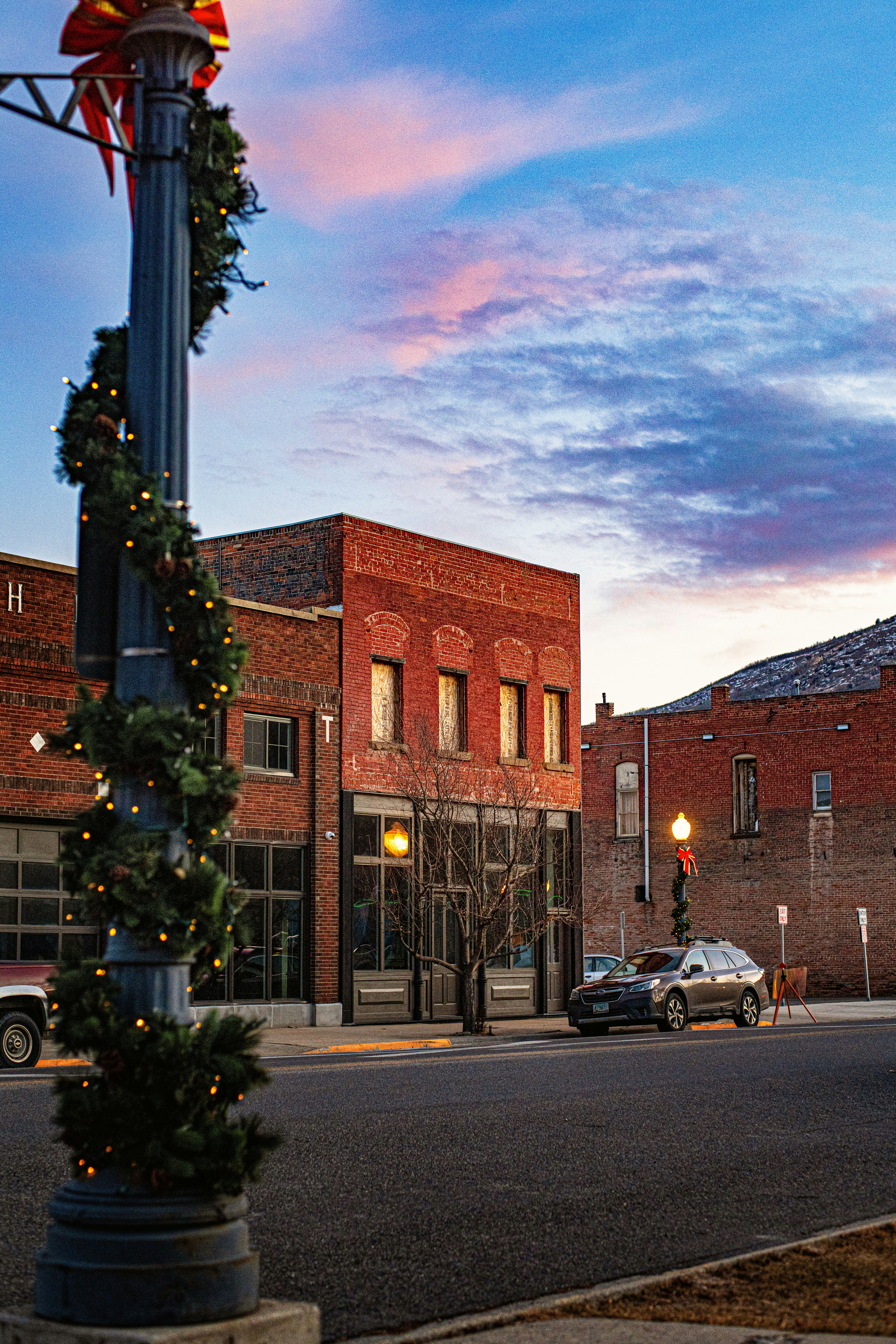 Dusk on Main Street: Garlanded Lamppost Framing a Brick Facade