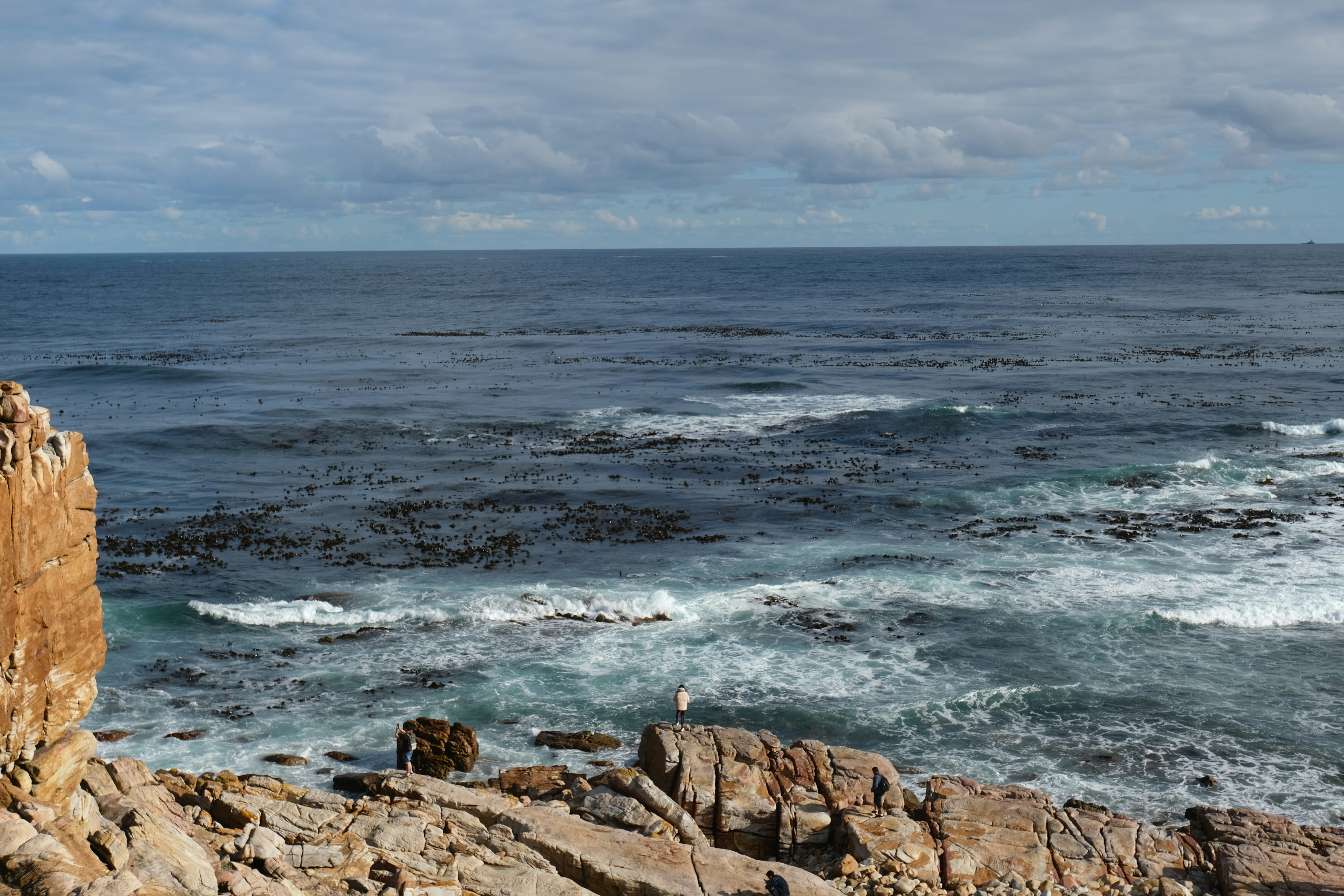 Expansive ocean view from rugged cliffs under a cloudy sky.