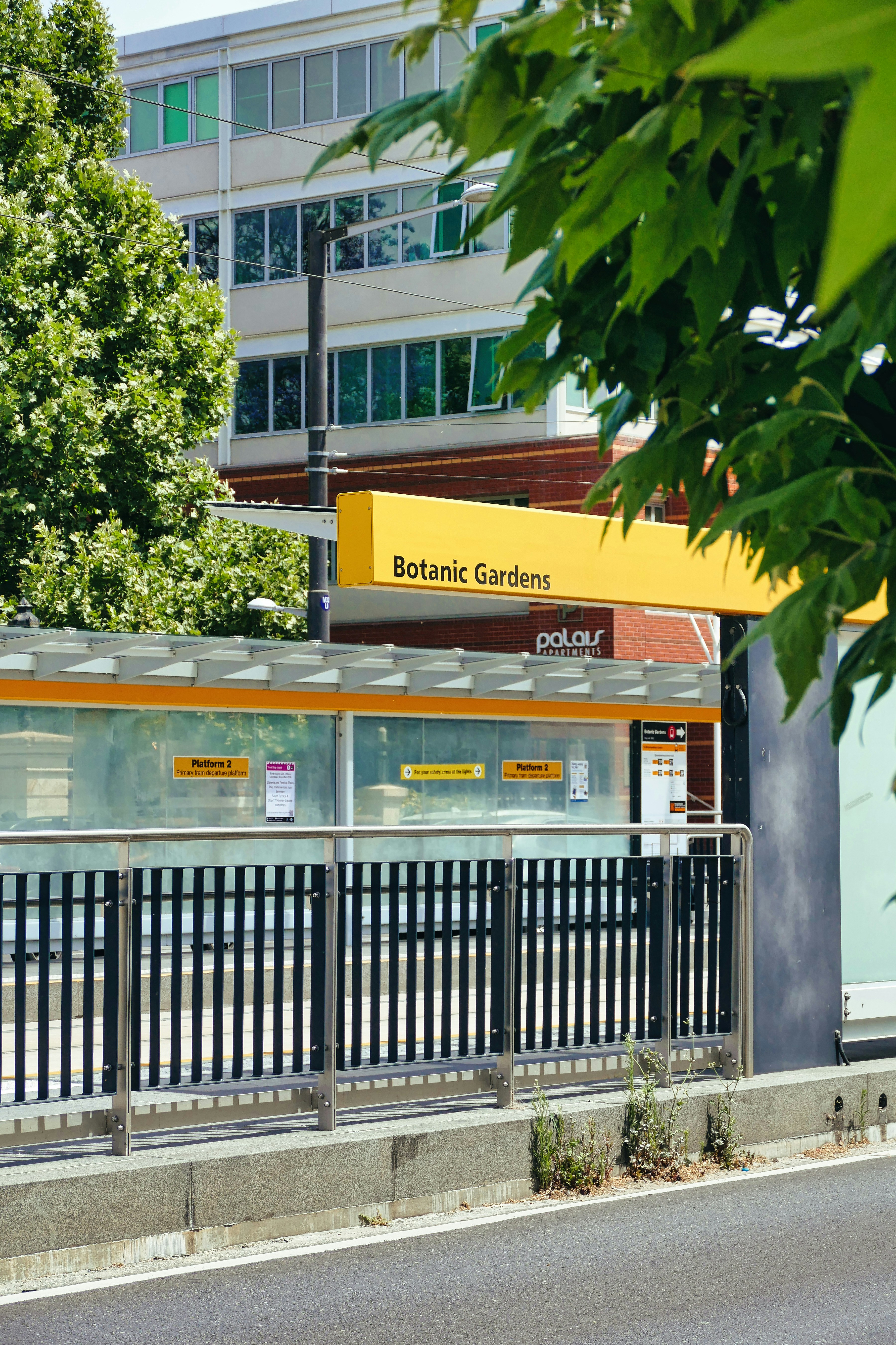 Botanic Gardens Station: A Yellow Sign Framed by Urban Green