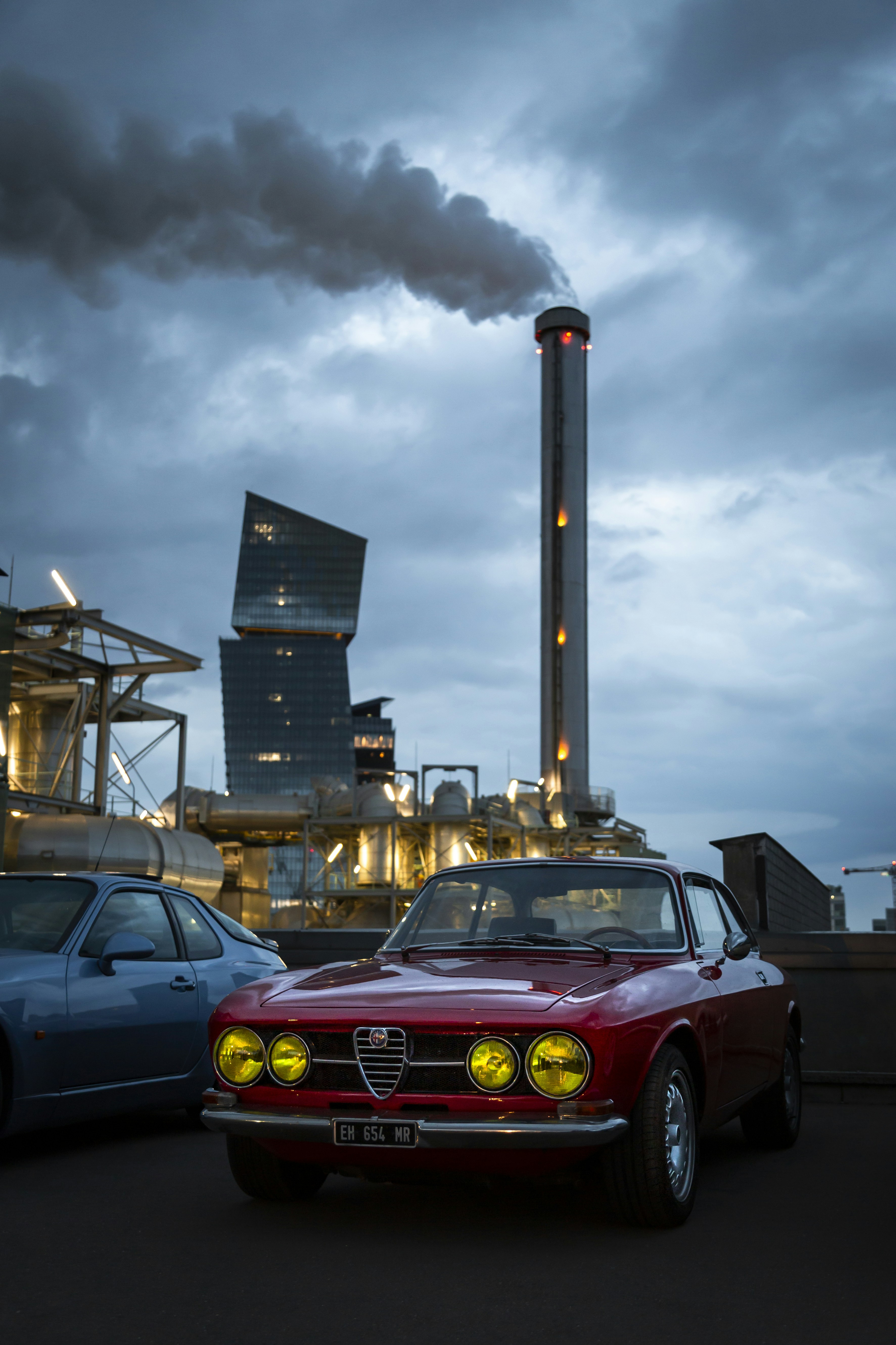 Crimson Convertible on a Rooftop Runway Under a Smokestack