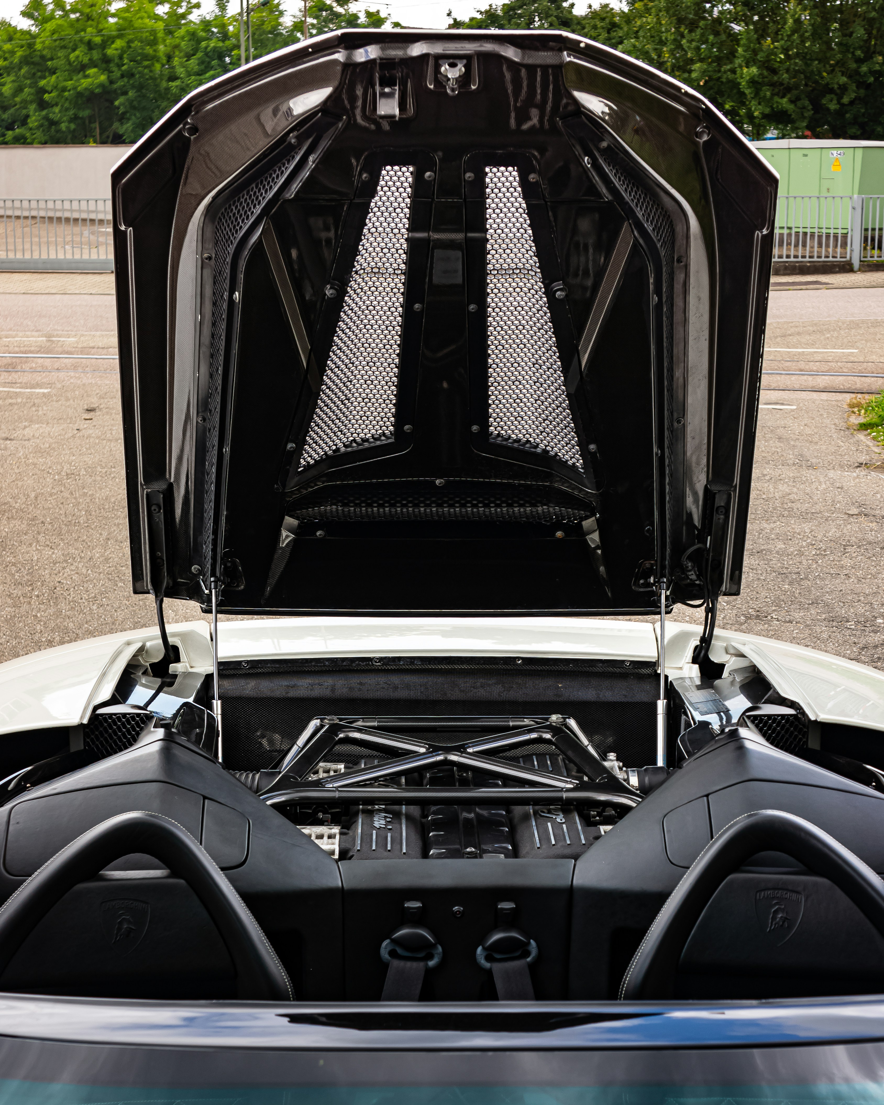 Rear engine bay of a high-performance sports car with open cover revealing intricate mechanics.