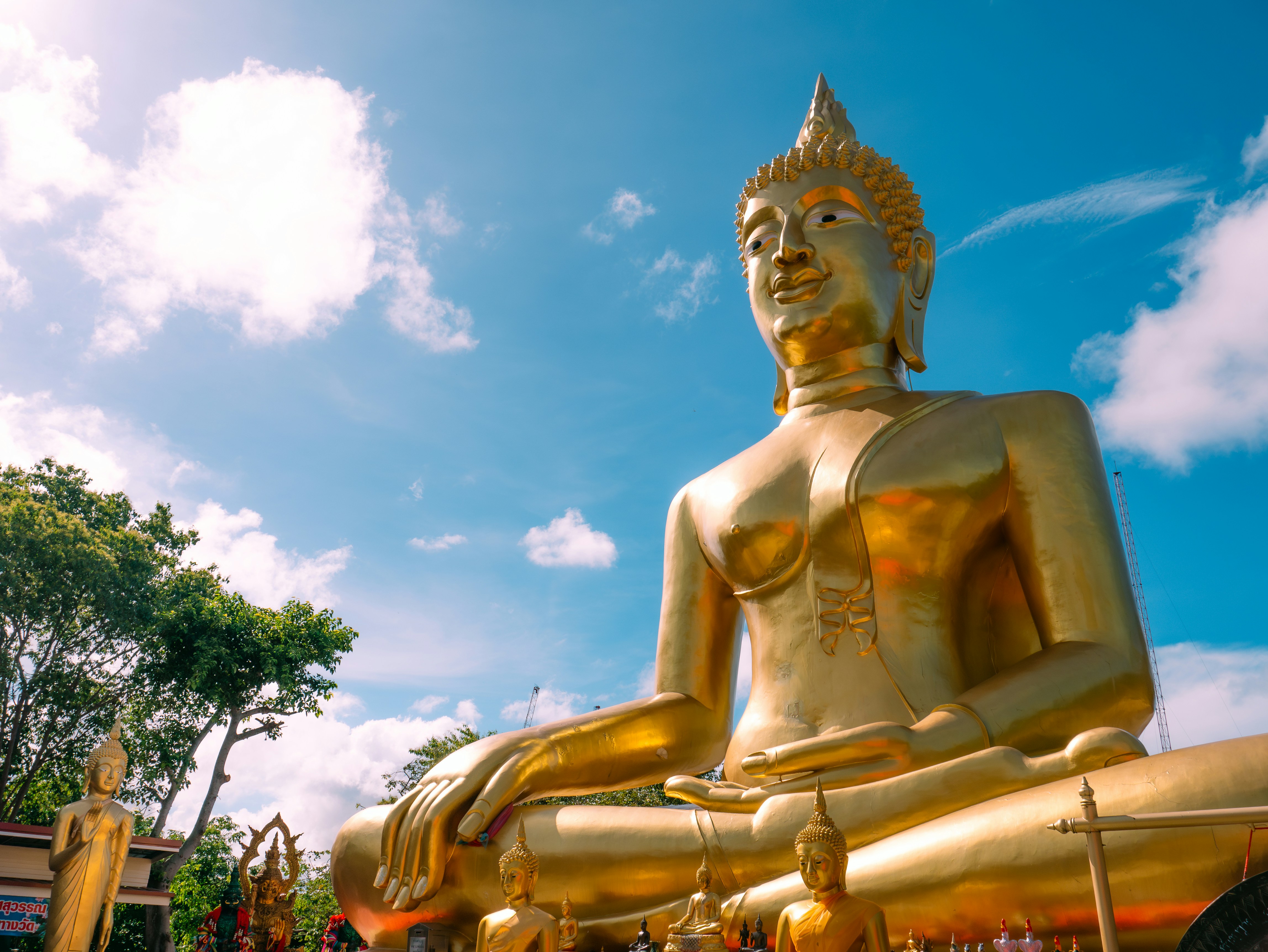 Golden Buddha statue against a vibrant blue sky with scattered clouds.