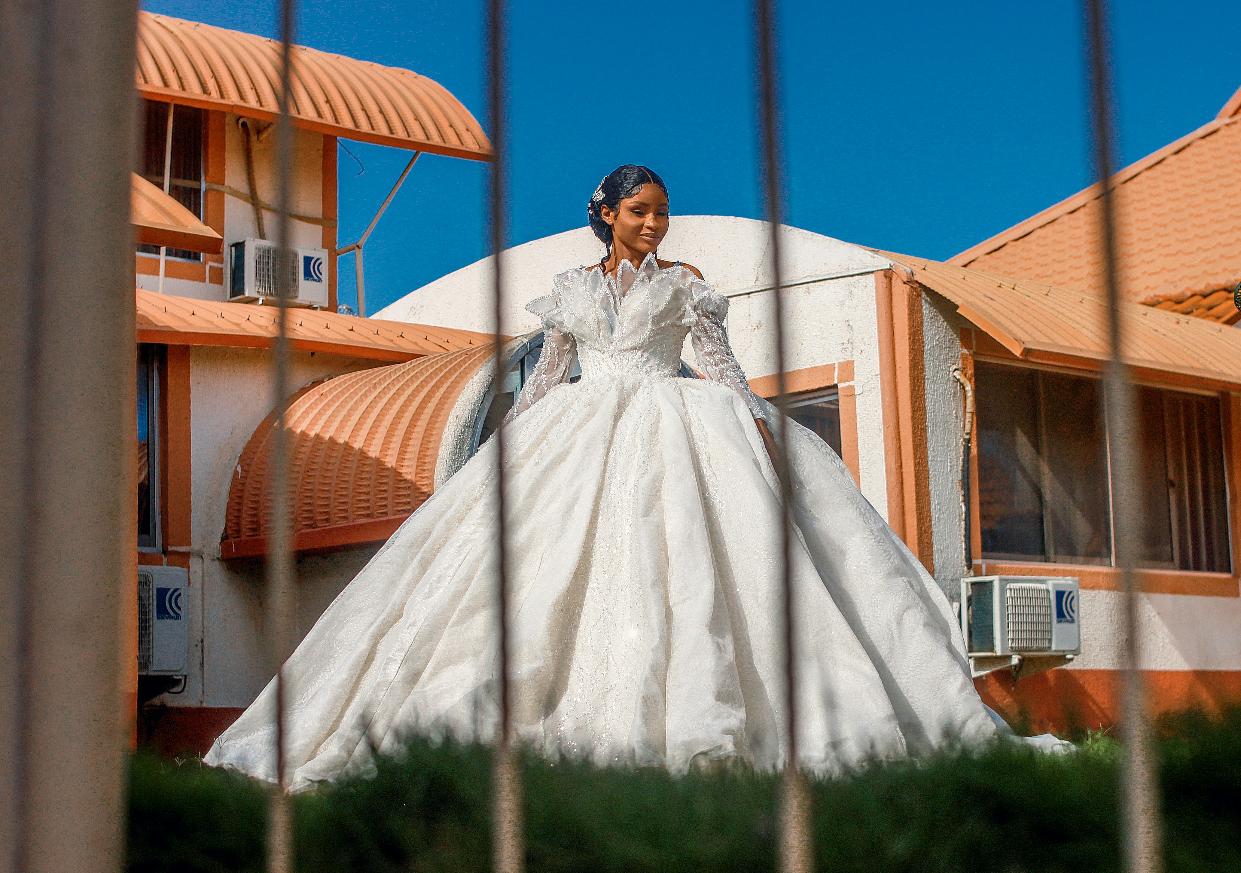 Ballgown in a Sunlit Courtyard: White Opulence Against Orange Rooftops