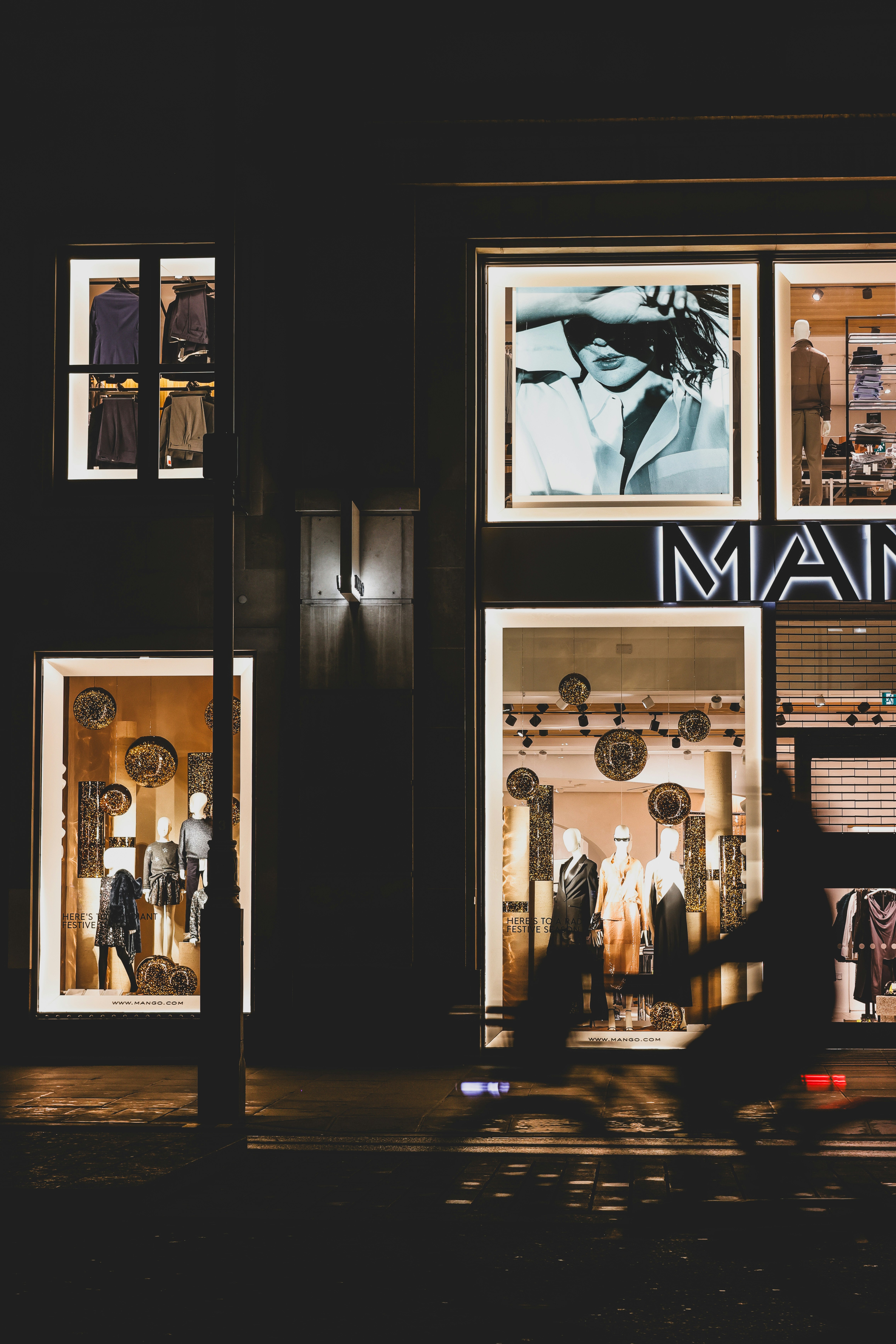 A man riding a bike past a store front at night photo – Free Street ...