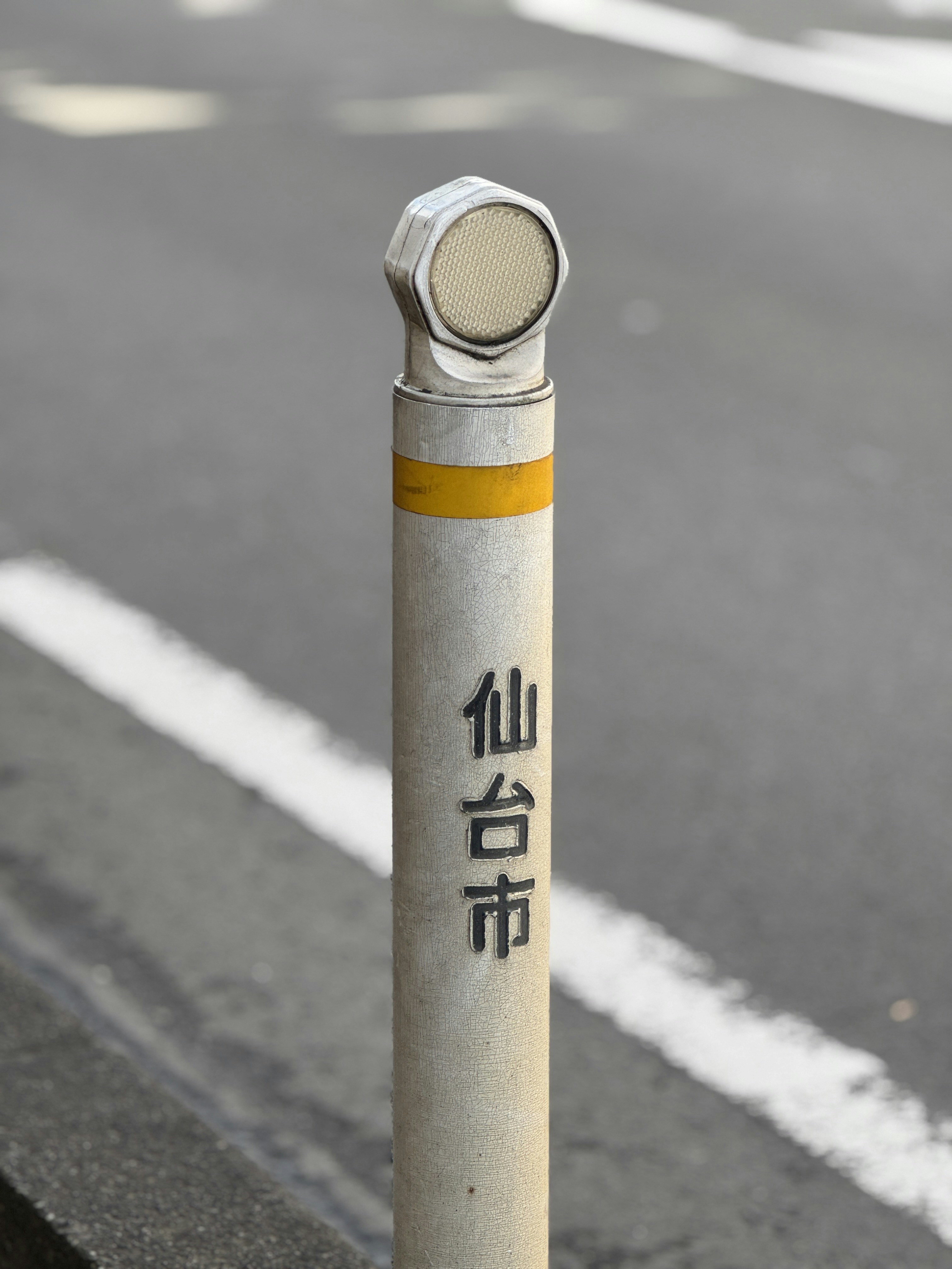 Sendai City Bollard: Weathered steel post with yellow band guarding a quiet street