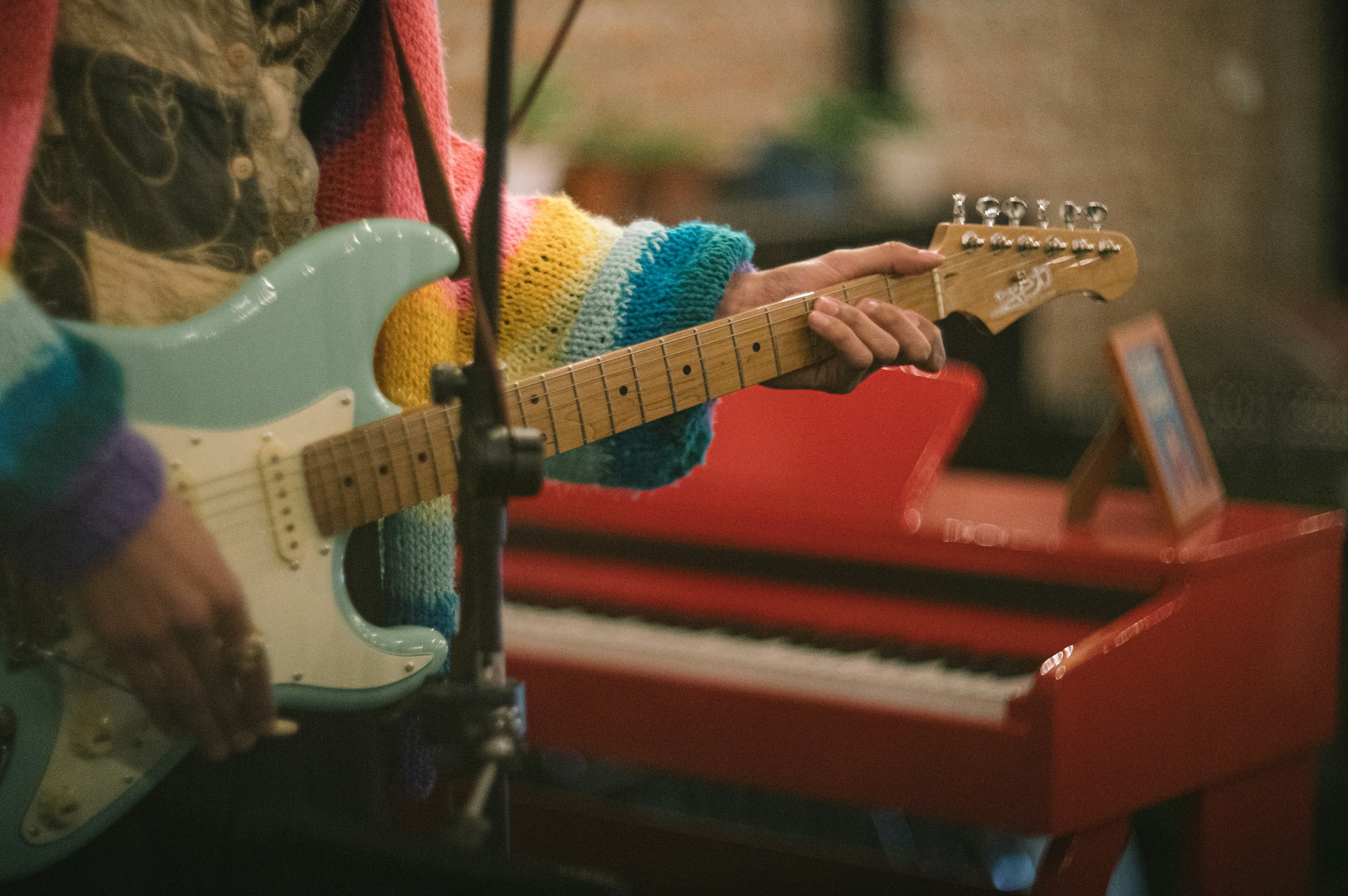 Cozy Jam: Mint Strat, Rainbow Knit, and a Red Piano in Focus