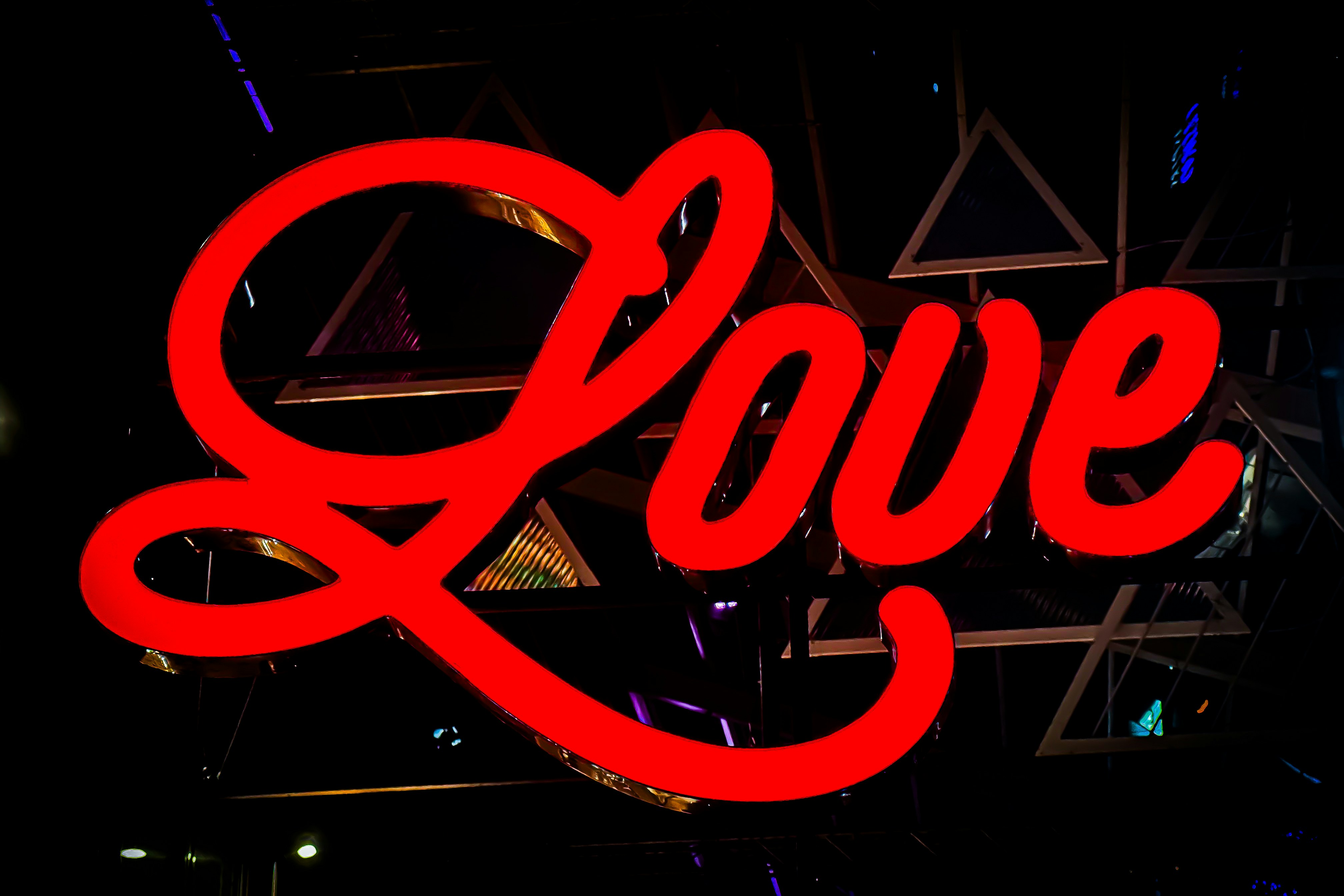 A large red love sign hanging from the side of a building photo – Free ...