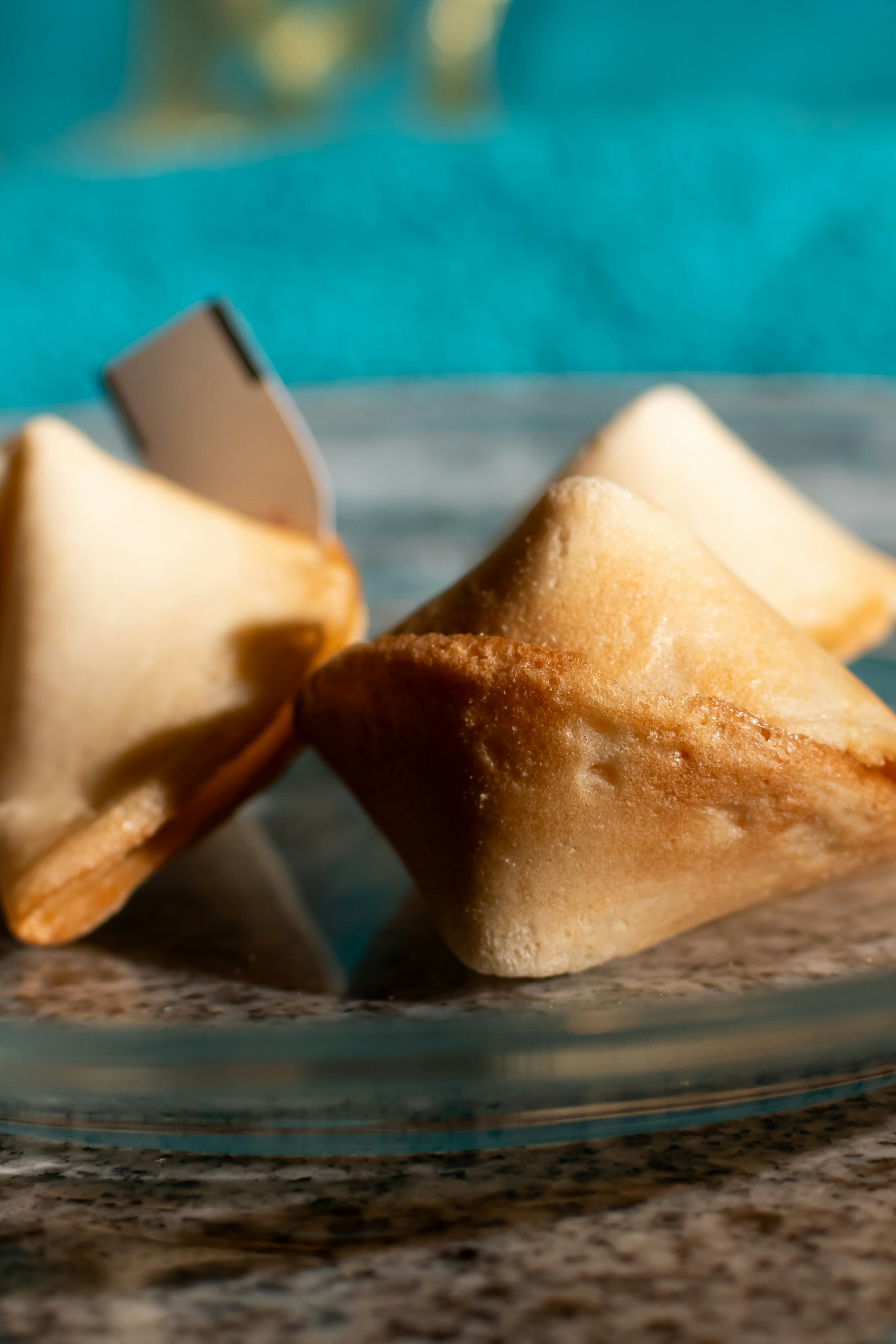 Golden Triangles on Marble: Crispy Pastries Rise Against a Turquoise Blur