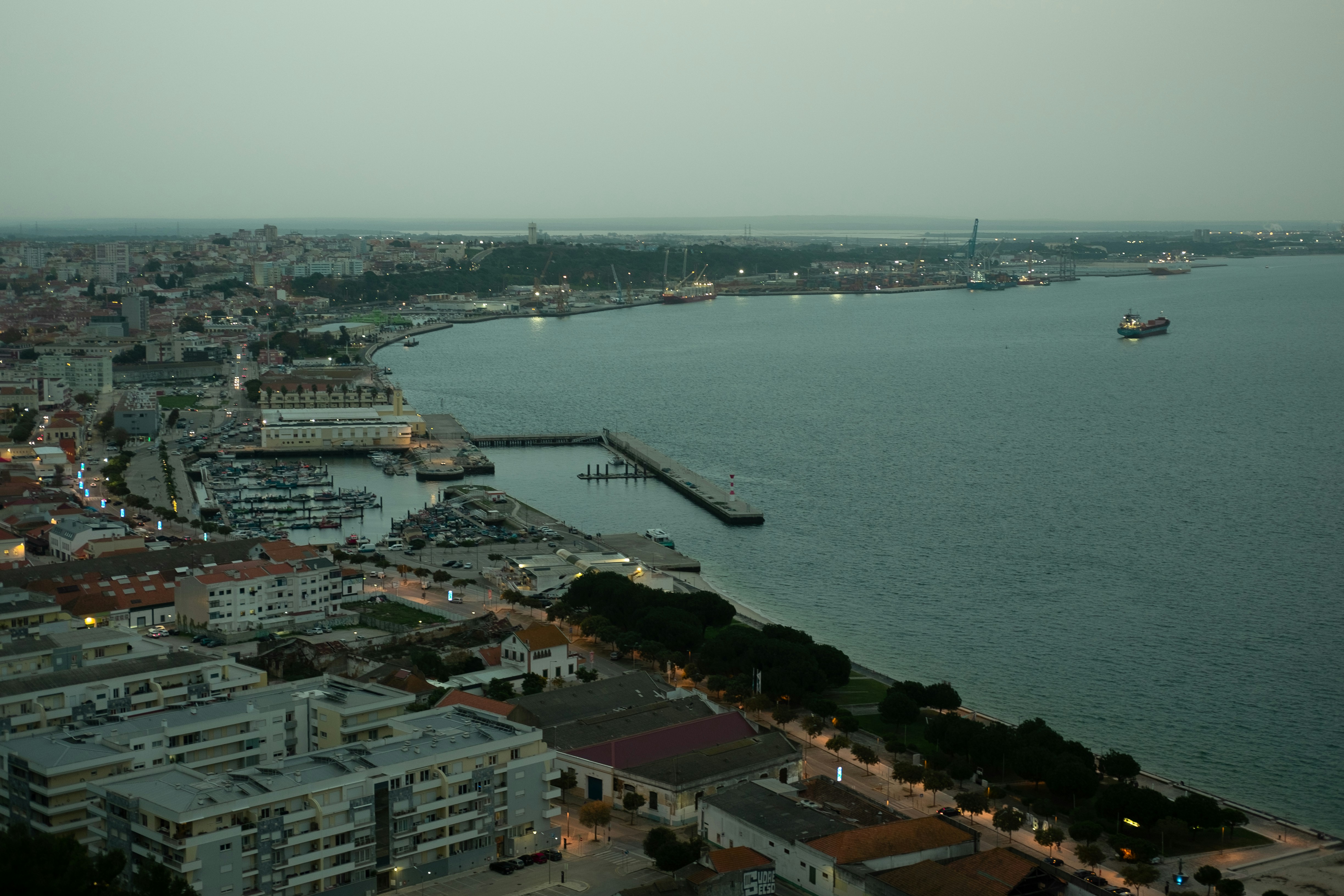 Harbor at dusk with cityscape and illuminated buildings along the waterfront.