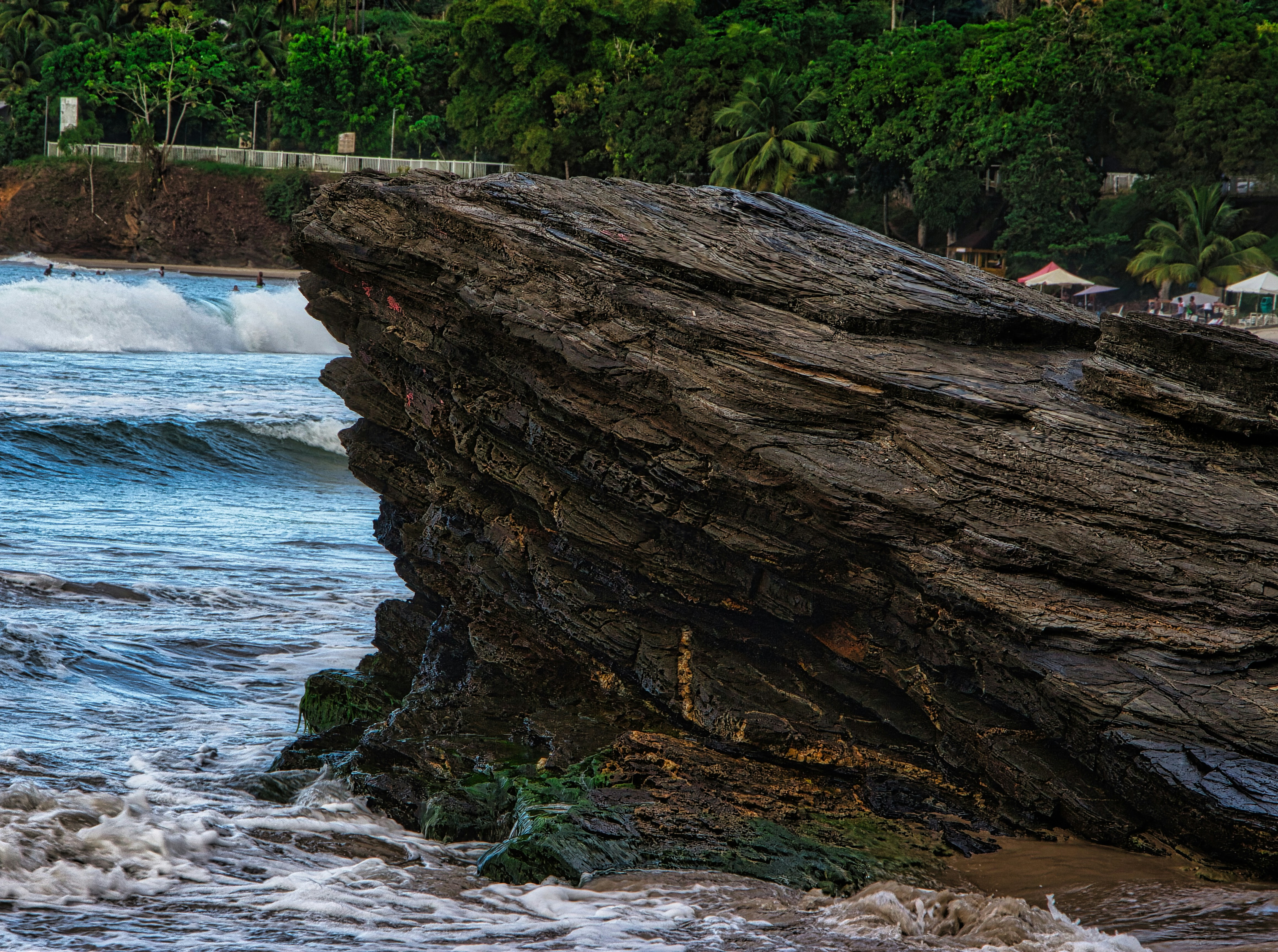 A large rock sticking out of the ocean next to a beach photo – Free Sea ...