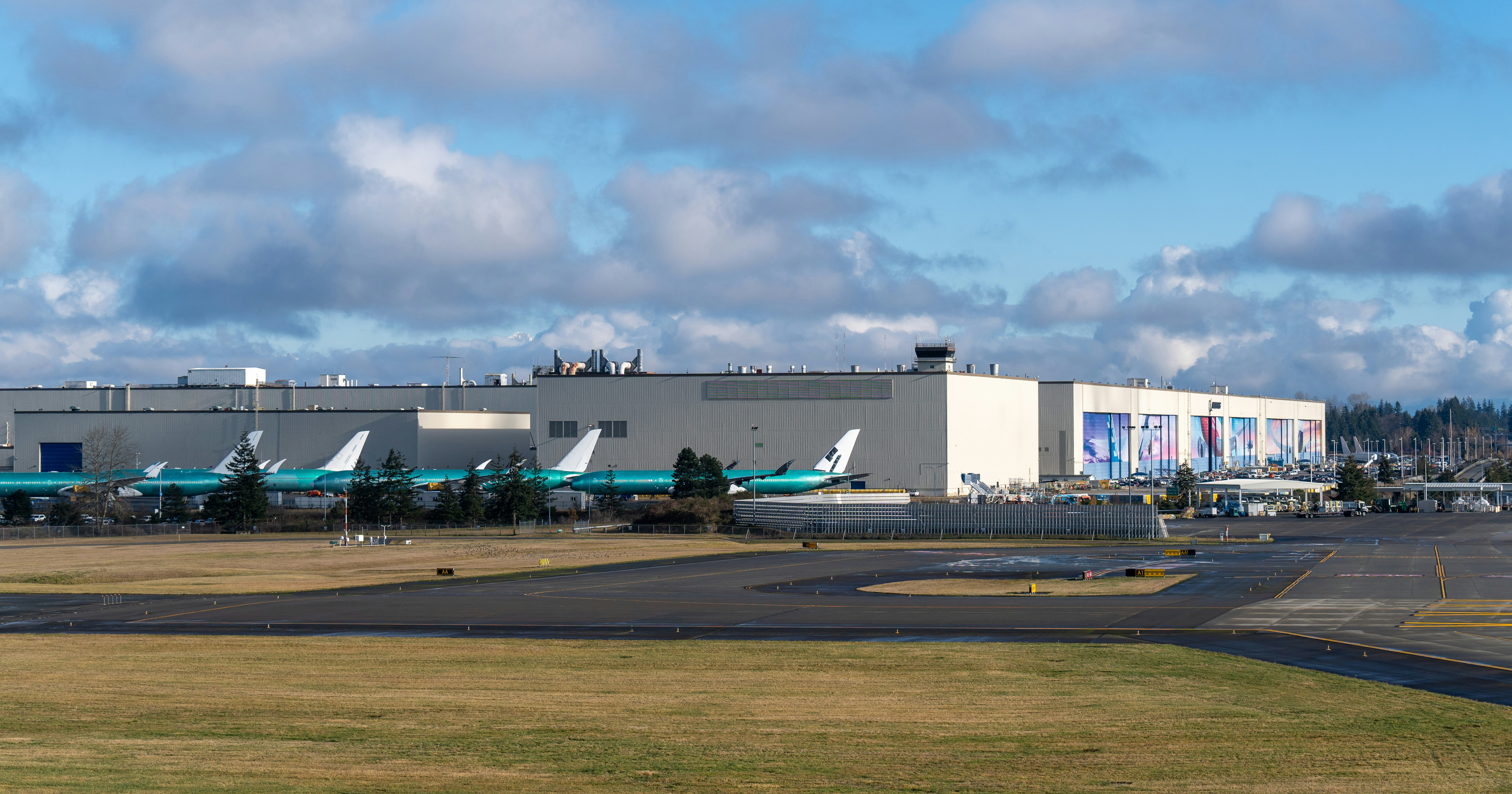 Teal Jets Align Along a Minimalist Airport Hangar