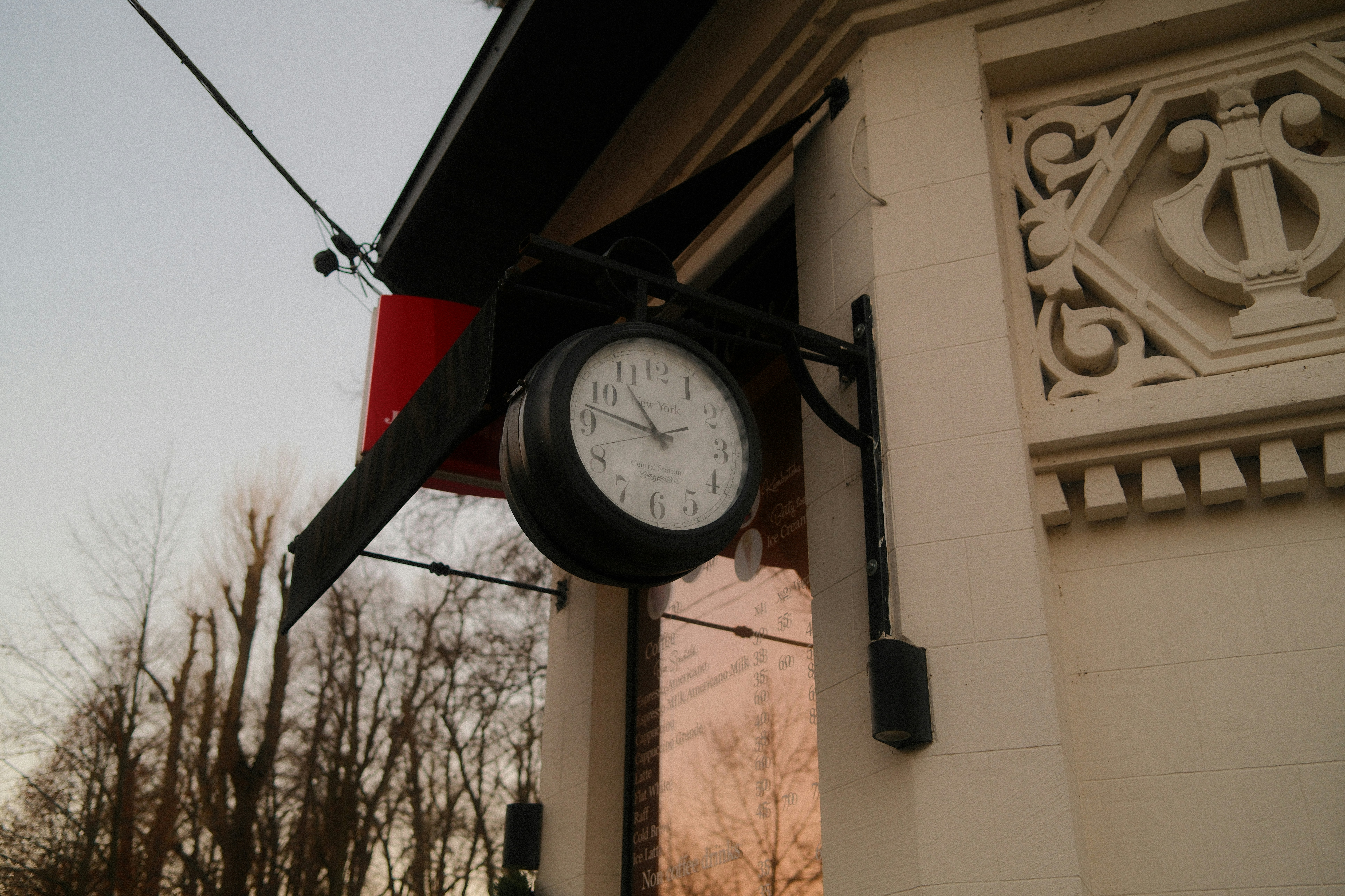 Hanging Clock Framing a Quiet Station Exterior