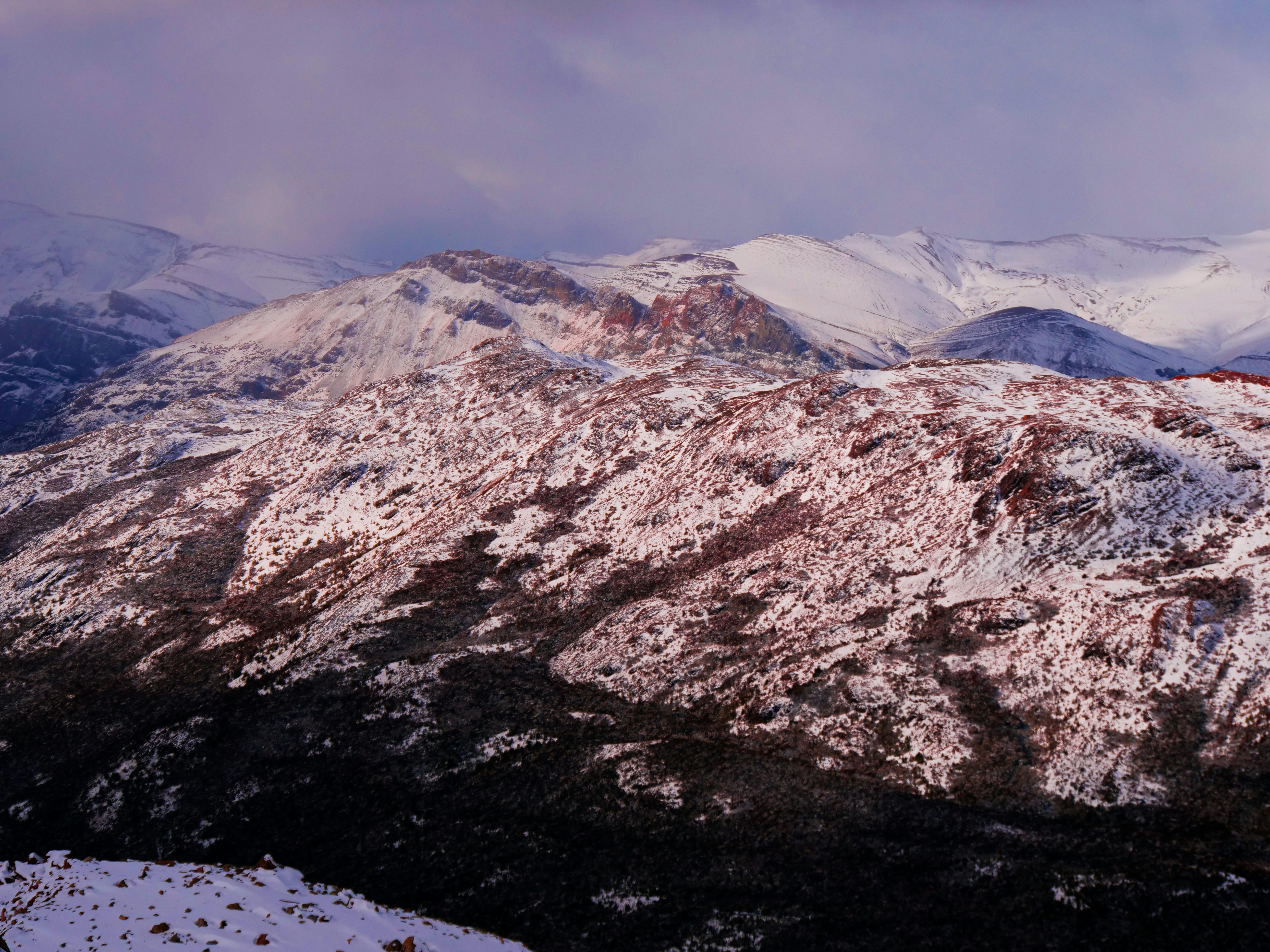 Snow-dusted mountains under a pastel sky, revealing intricate textures and gentle light contrasts.