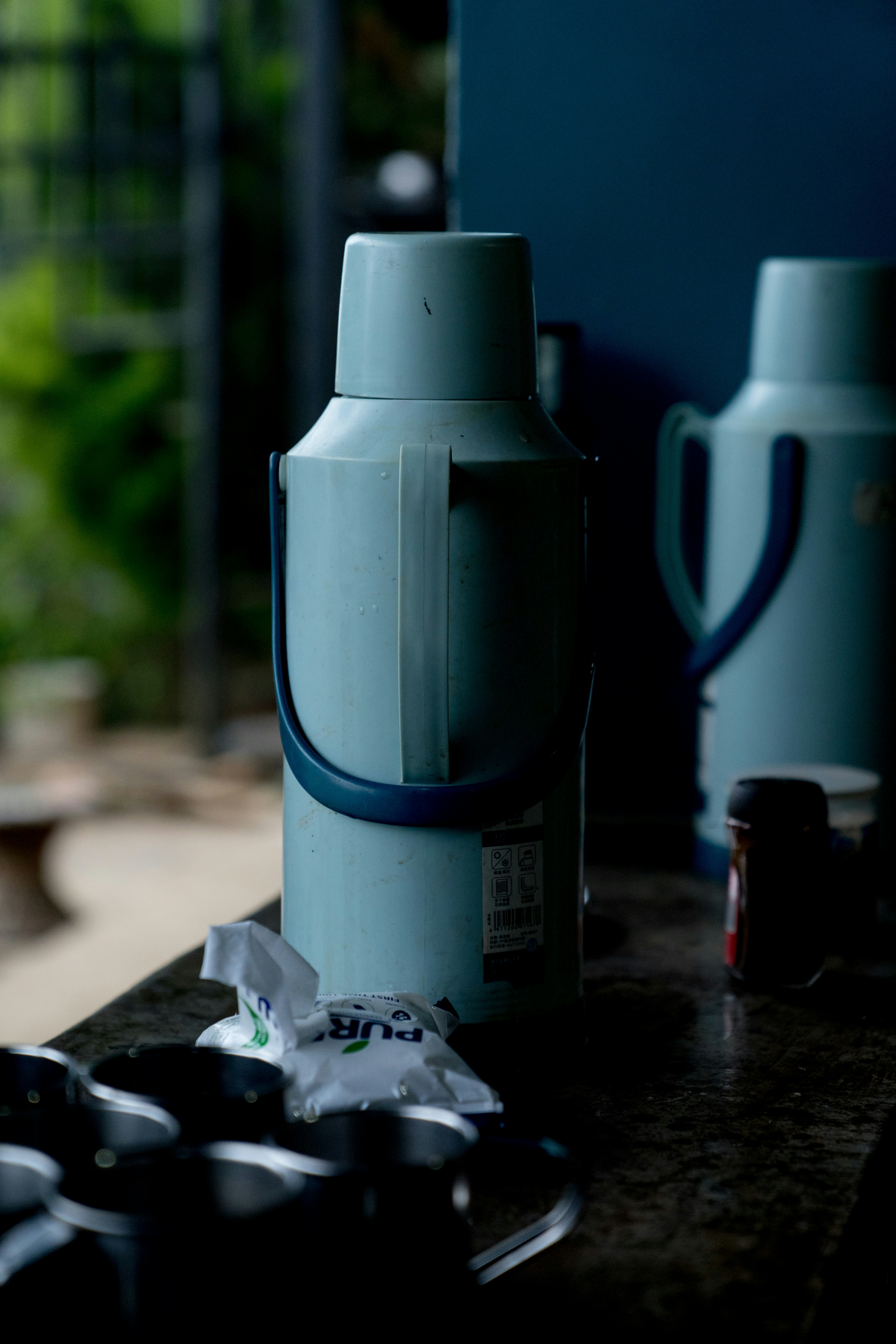 Blue Thermoses on a Dim Counter: Quiet Evening Light