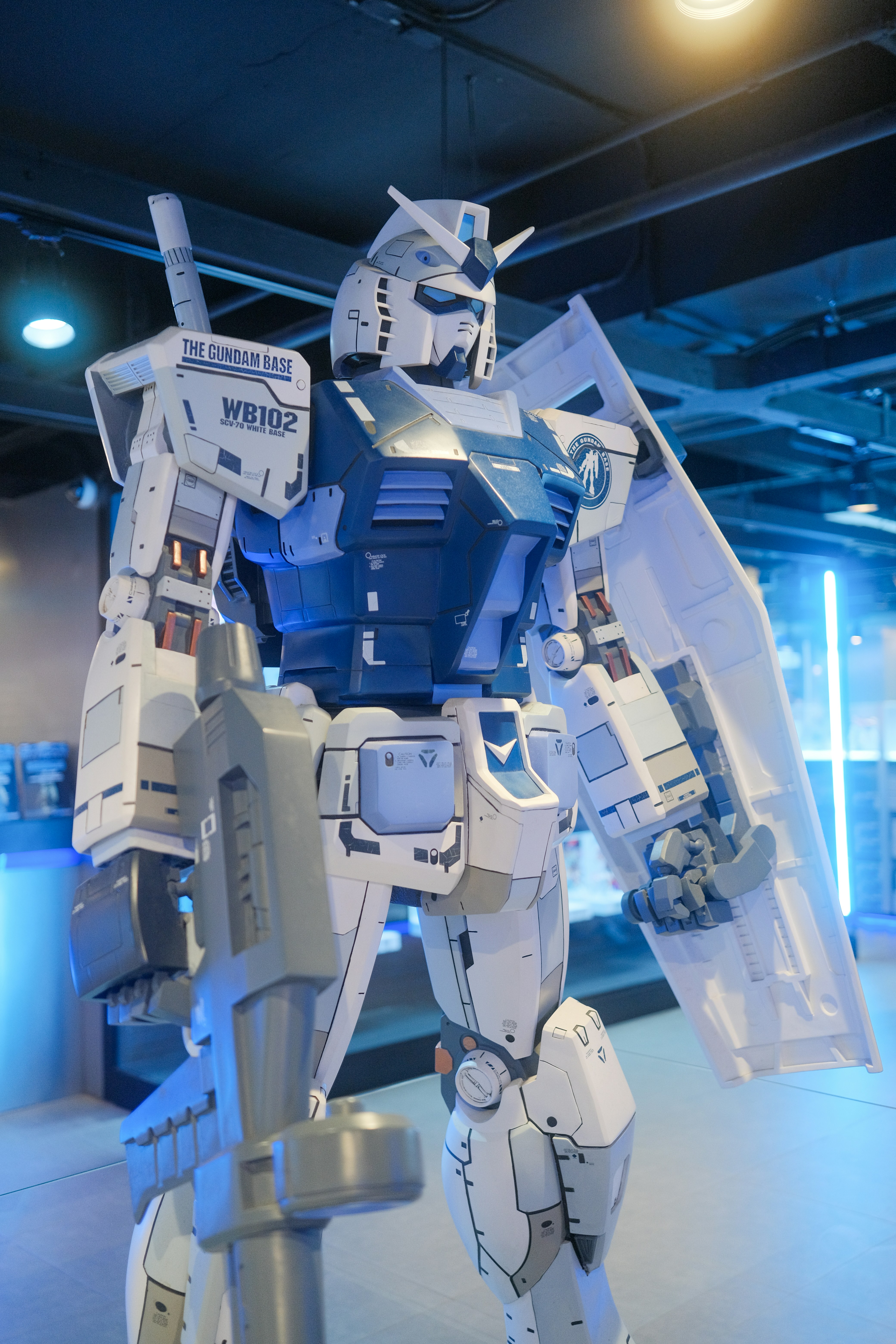 Neon-Blue Guardian: The Gundam Statue Amid a Neon Museum Glow