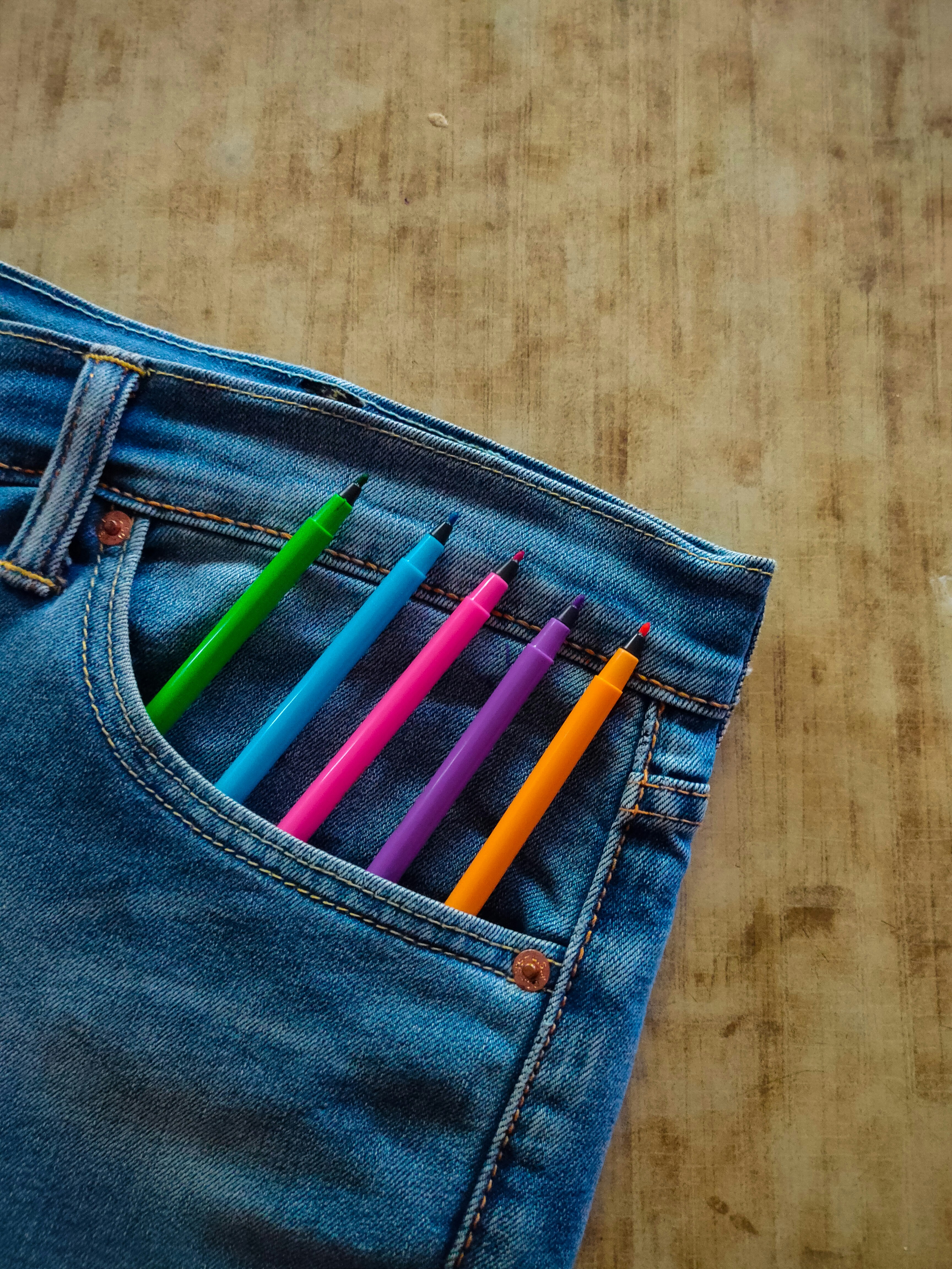 A pair of jeans with colored pencils sticking out of it