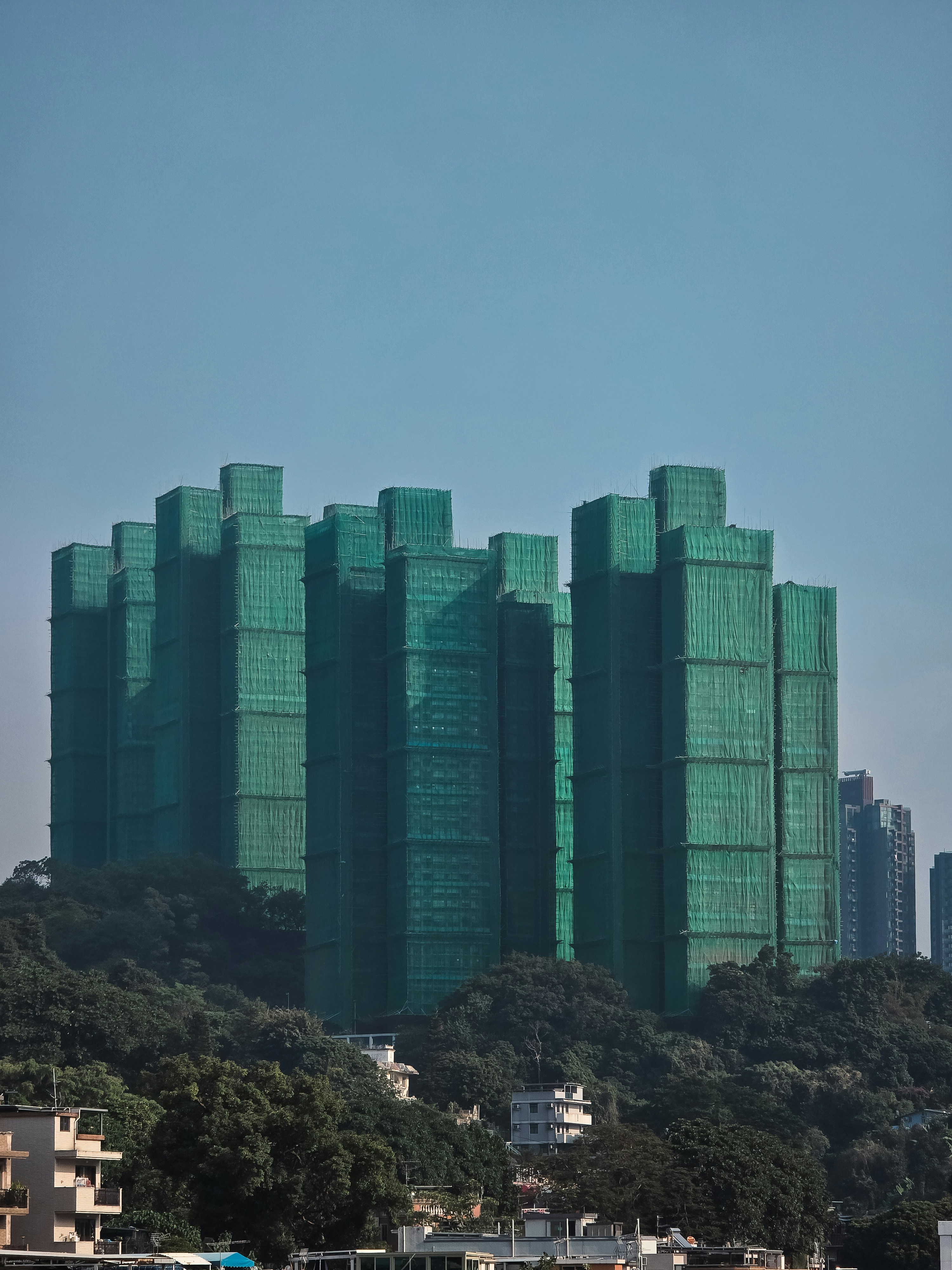 Emerald Towers: Scaffolded Giants Rising Against a Clear Blue Sky