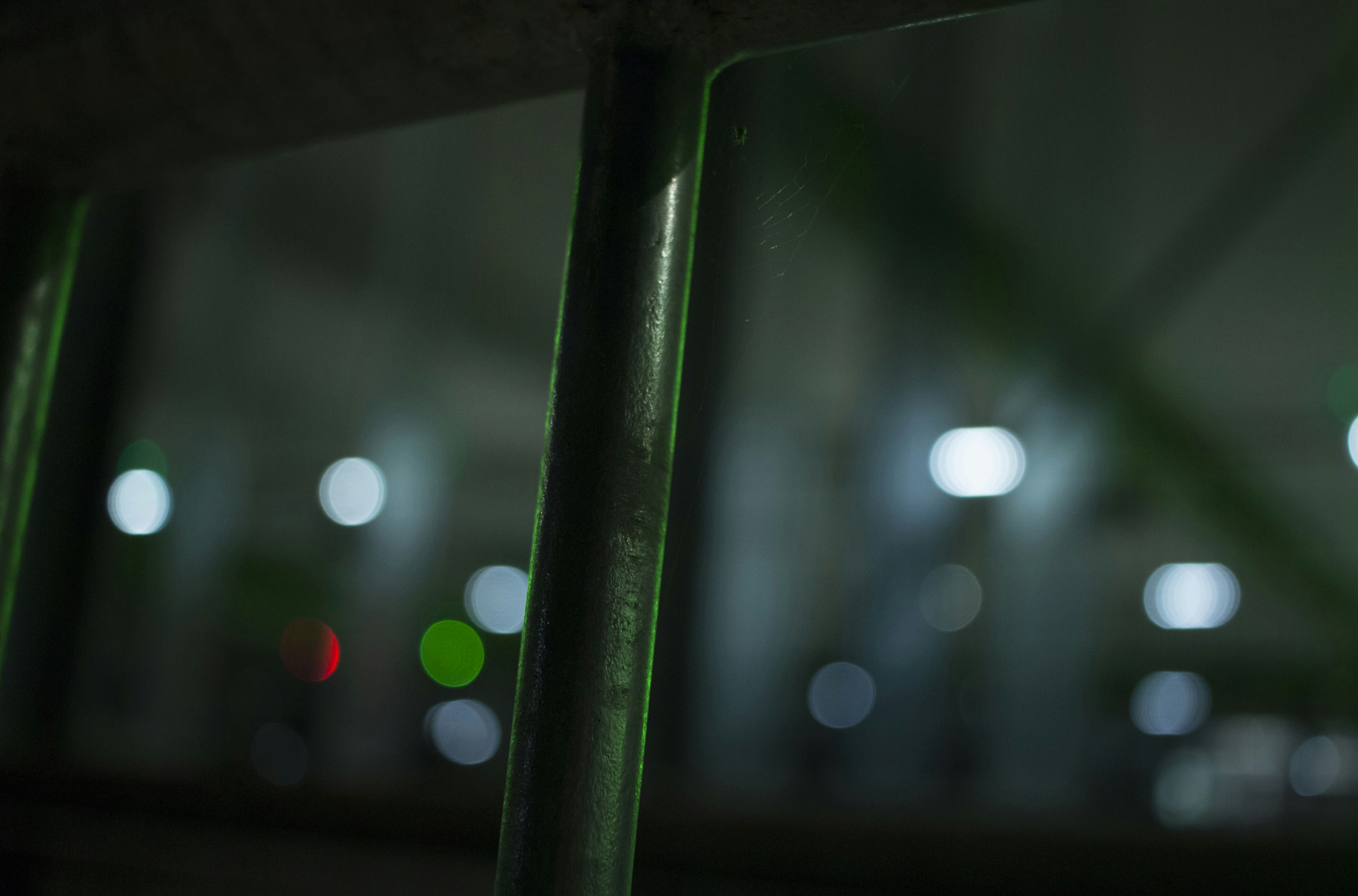 Green-rimmed Rail in a Night arcade: a close-up of metal frames against blurred city lights