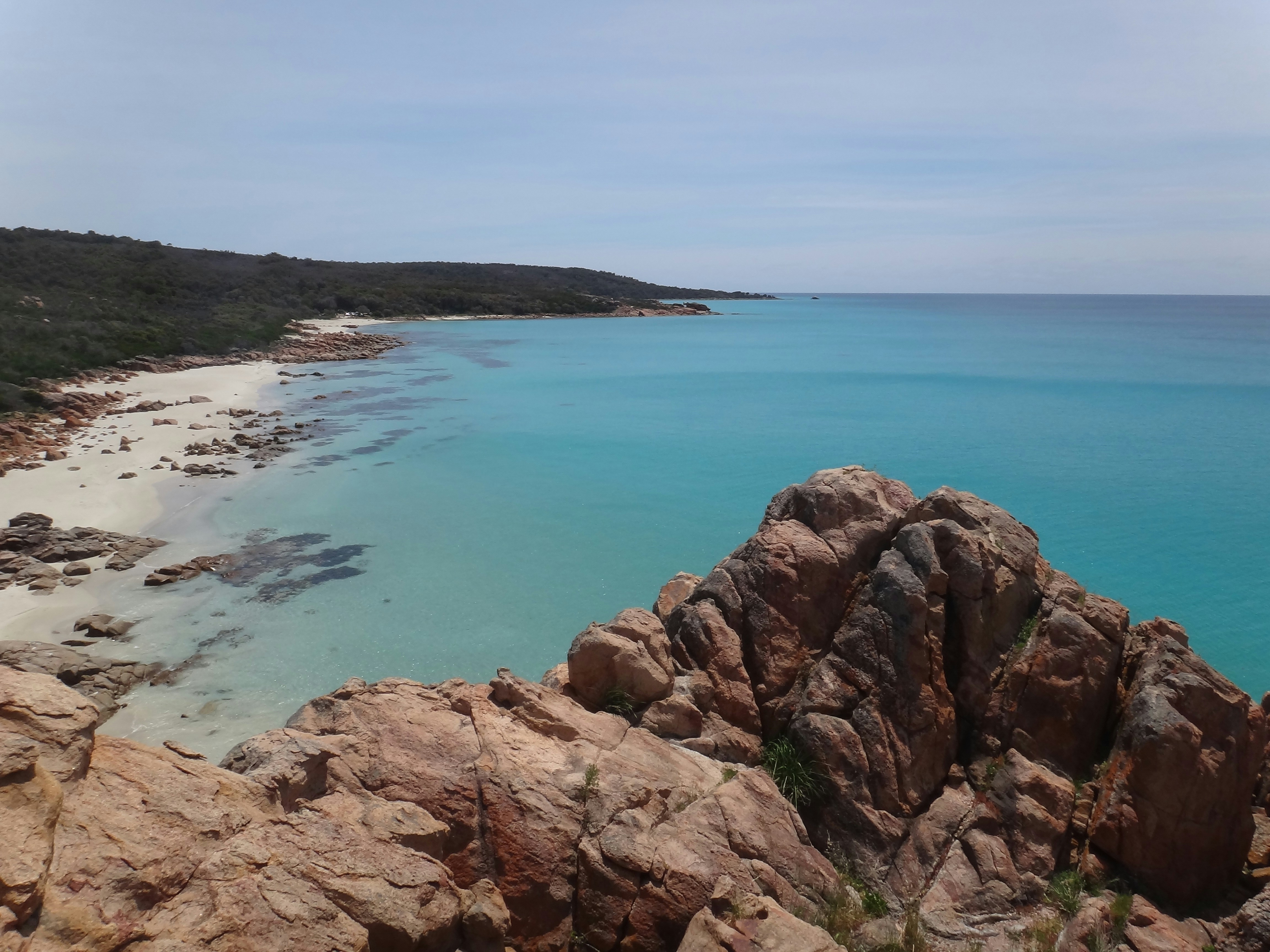 Rocky coastline with turquoise waters stretching into the horizon under a clear sky.