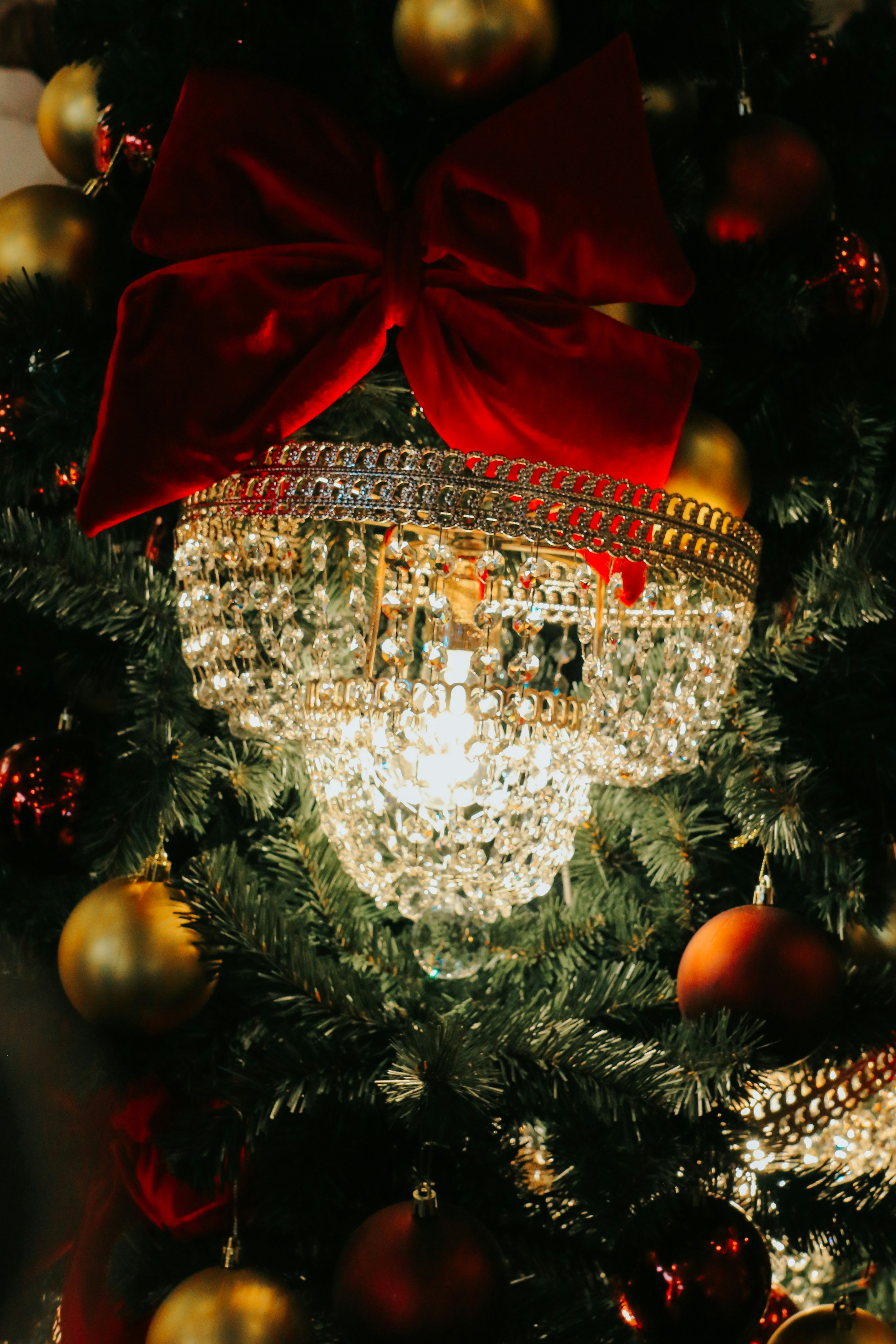 Crystal Chandelier Glow Framed by Red Ribbon and Evergreen