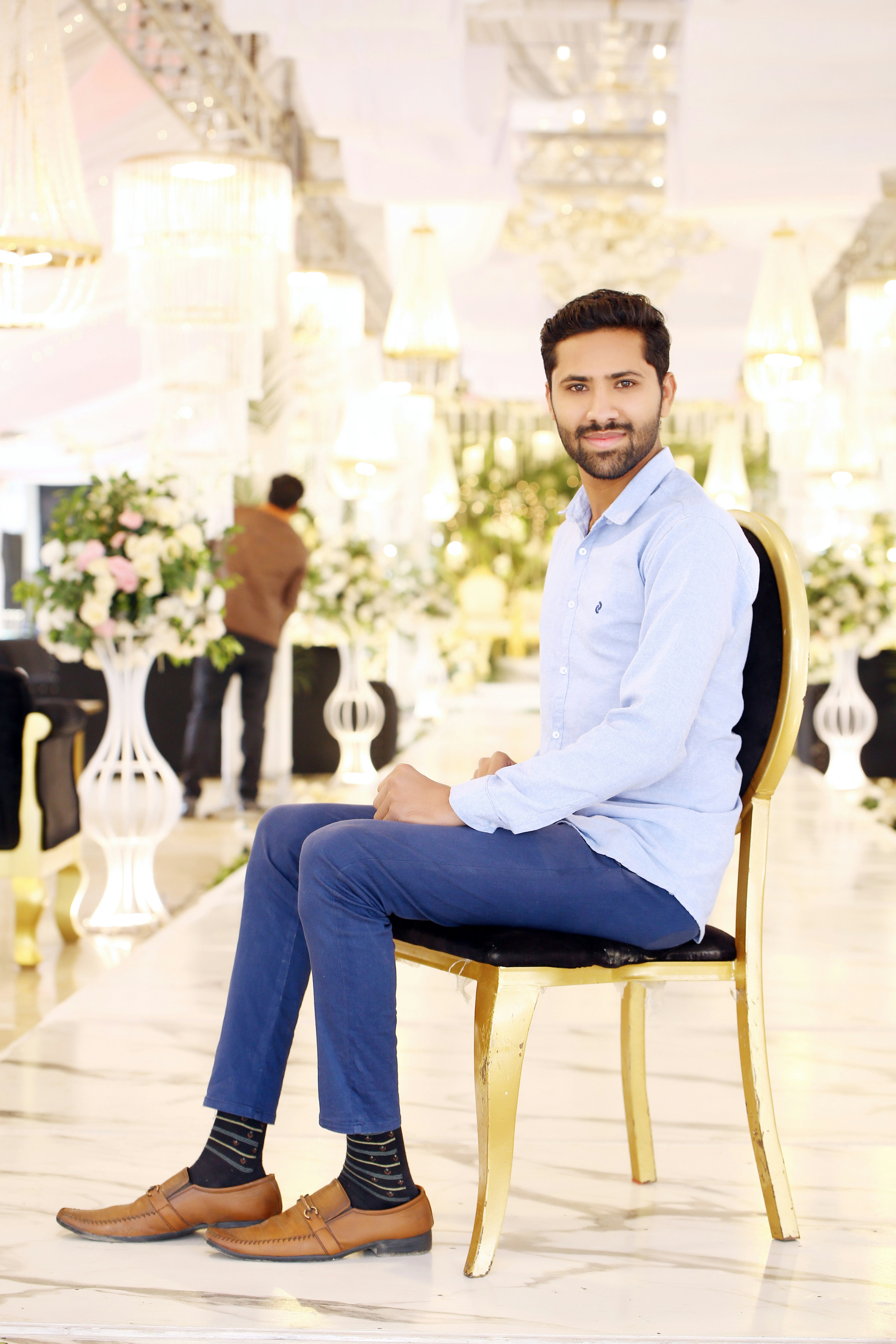 Sunlit Poise: A Seated Gentleman in a Chandelier-Lit Ballroom