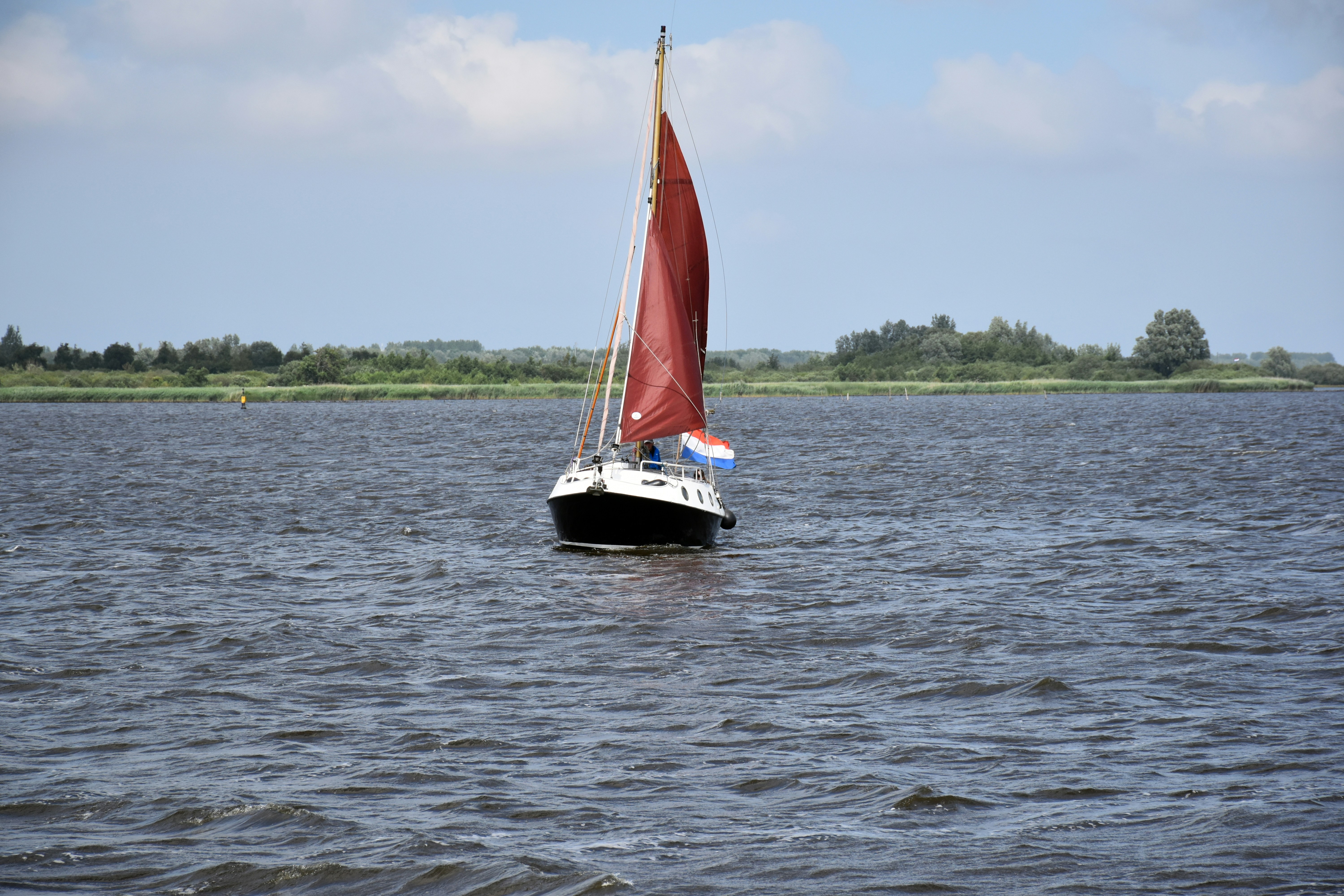 Red-Sailed Vessel Navigates a Quiet Waterway