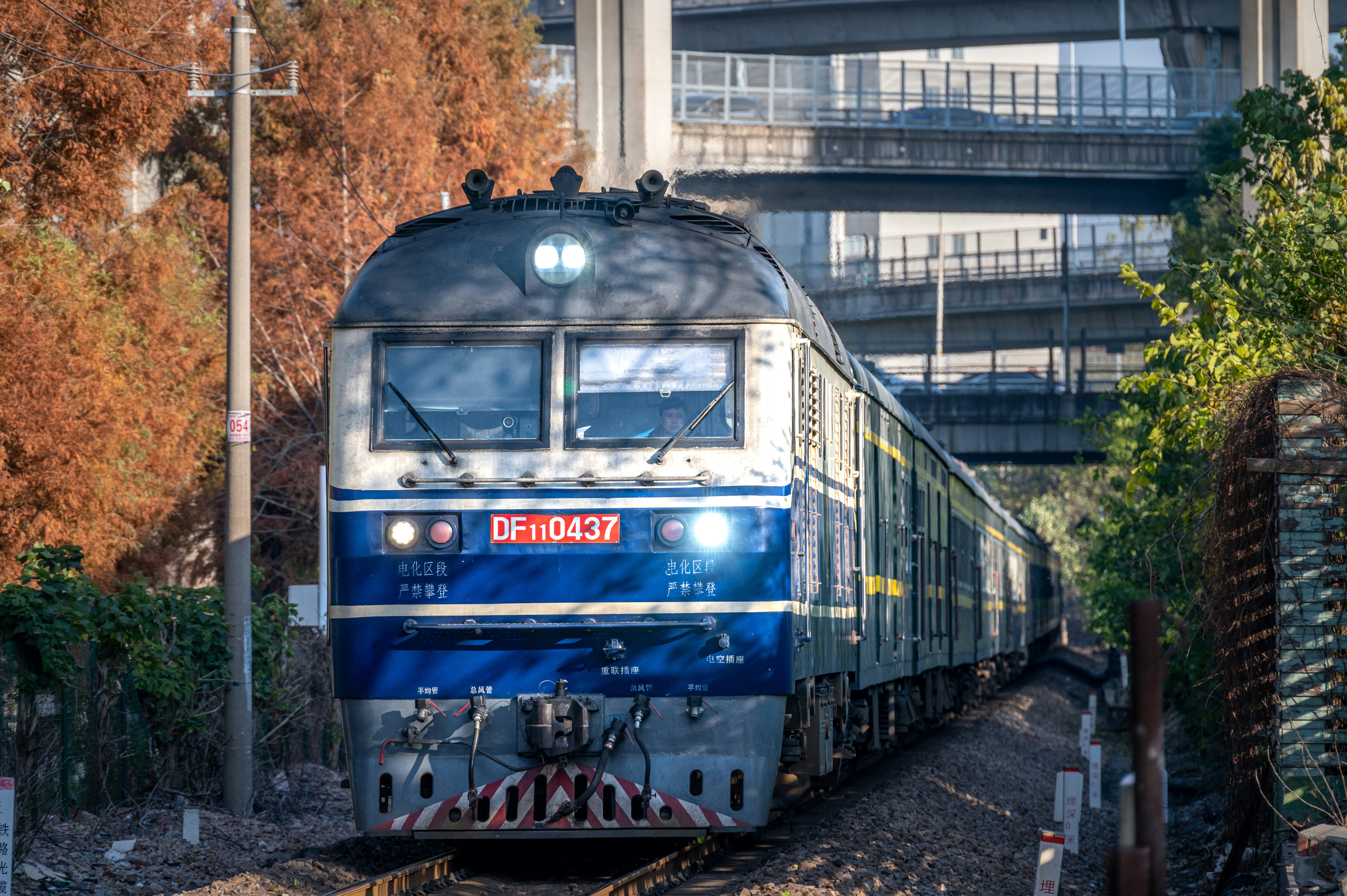 A blue and silver train traveling past a tall building photo – Free ...