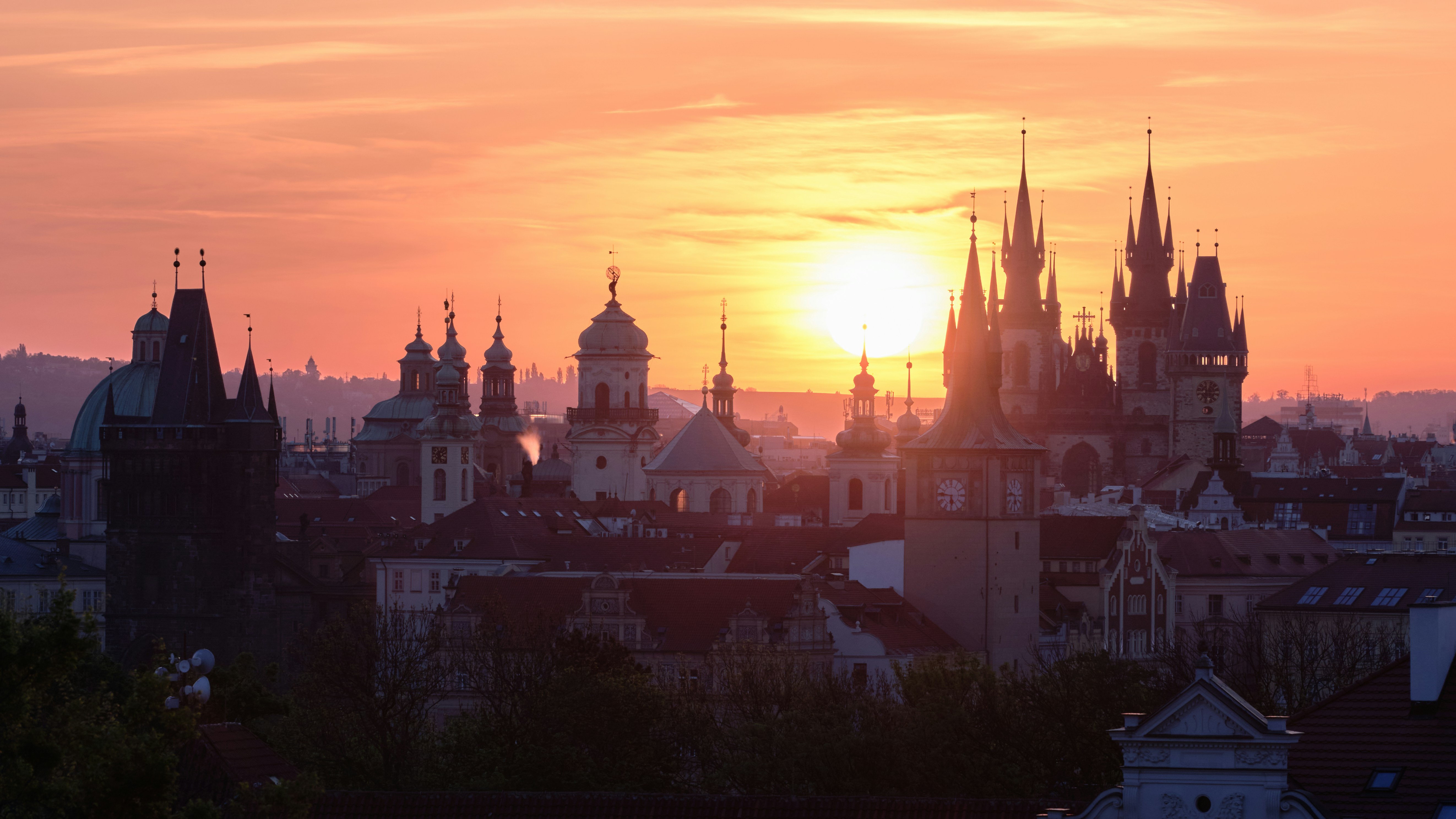 The sun is setting over a city with tall buildings photo – Free Prague ...