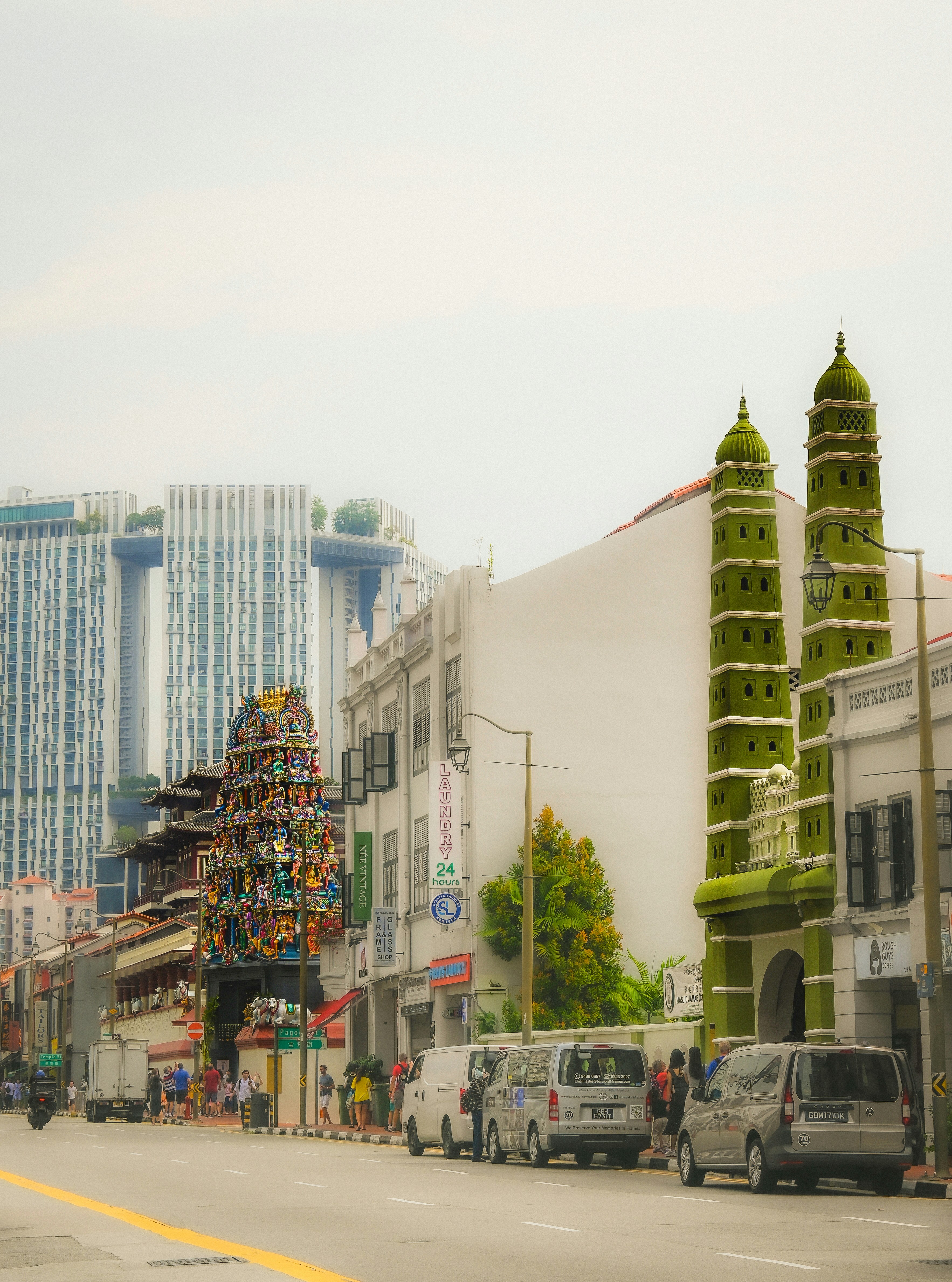 Religious tolerance and coexistence are key tenets of Singaporean society. There is no better example of this than the juxtaposition of Jamae Masjid, a mosque dating to 1820, and Sri Mariamman Temple, Singapore’s oldest Hindu temple. | A city street filled with lots of tall buildings