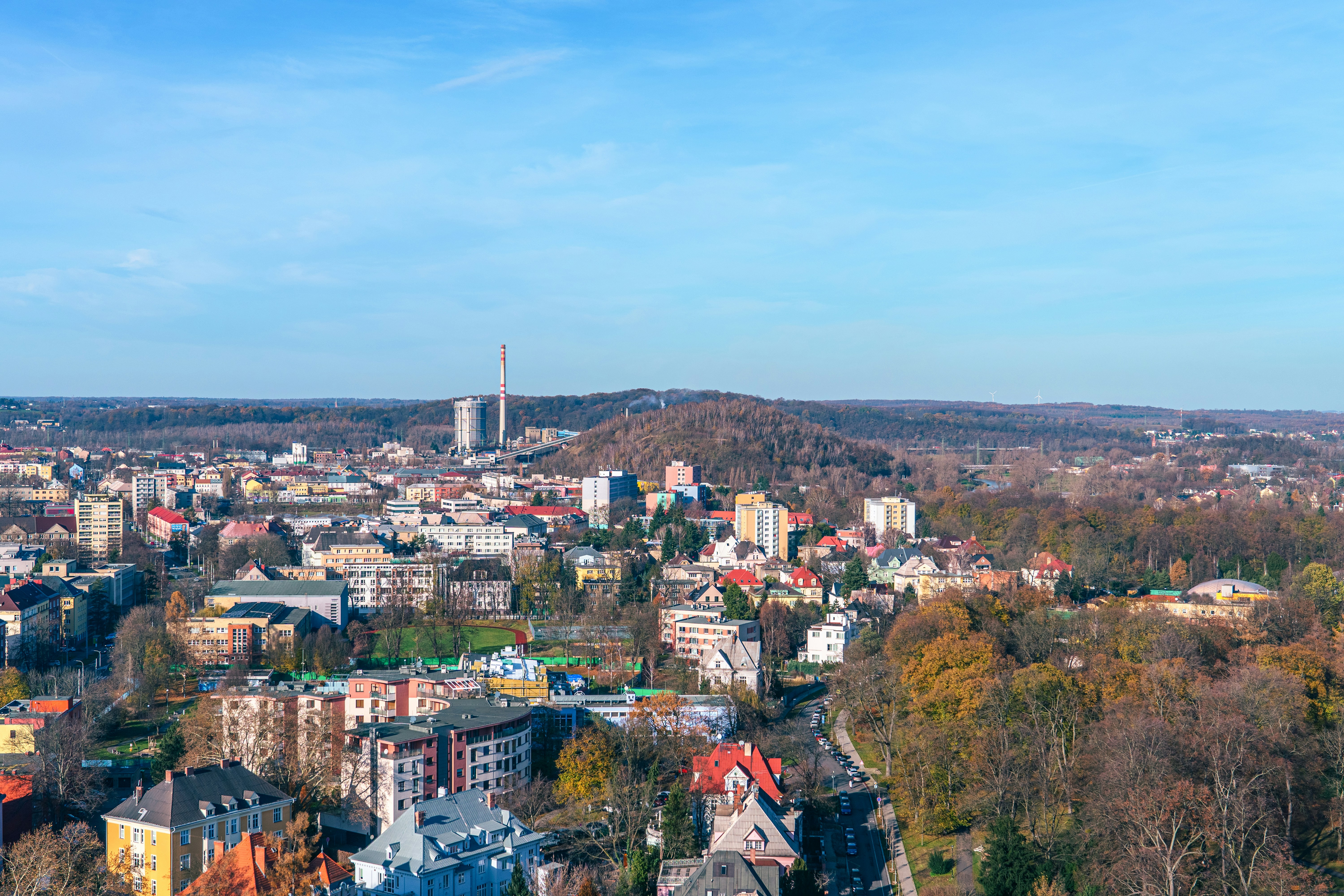 Panoramic view of Ostrava's cityscape with buildings and a distant hill under a clear blue sky.