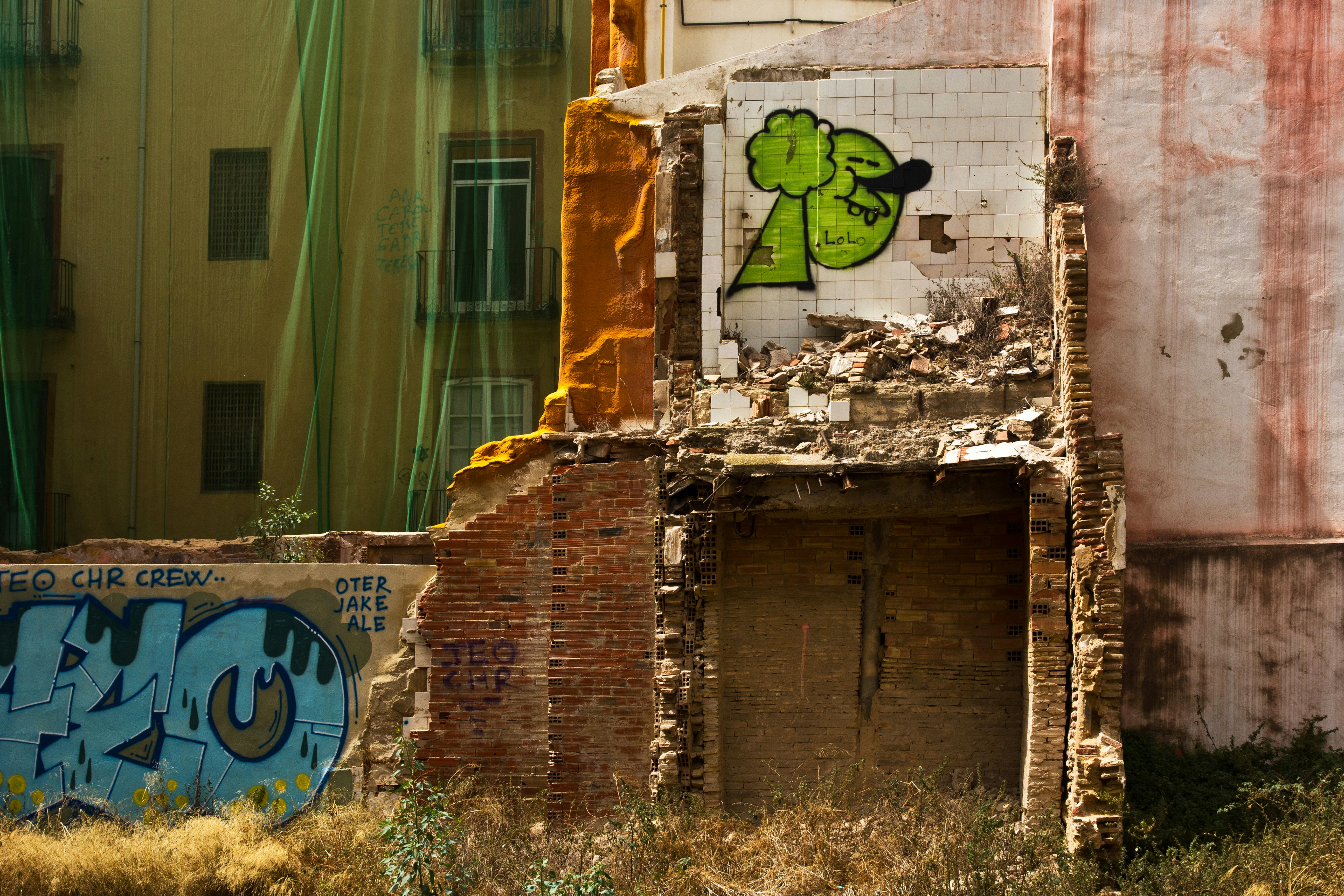 Graffiti on a partially demolished building with vibrant green and blue designs.