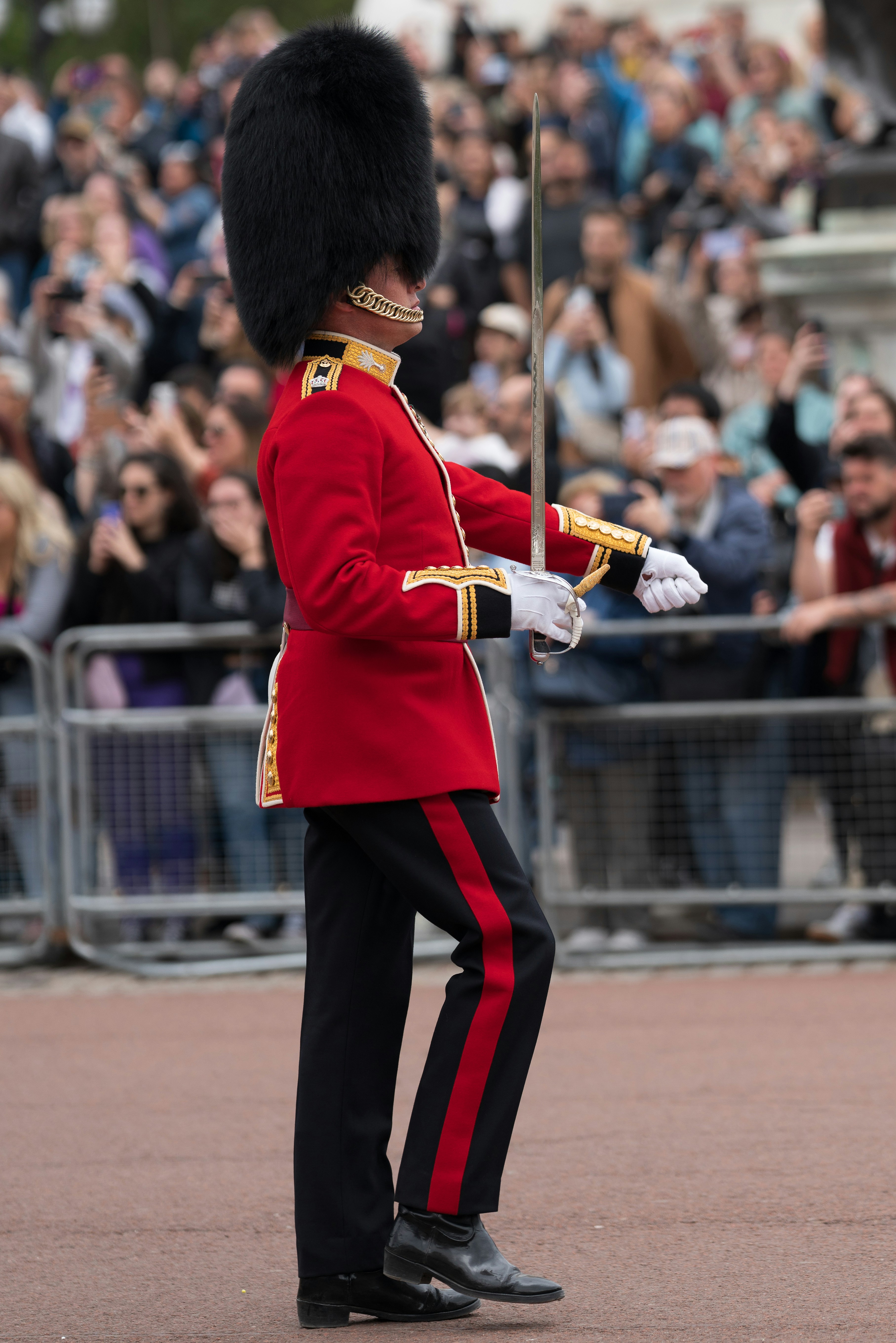 Ceremonial Guard in Red Regalia Mid-Stride with Sword Raised