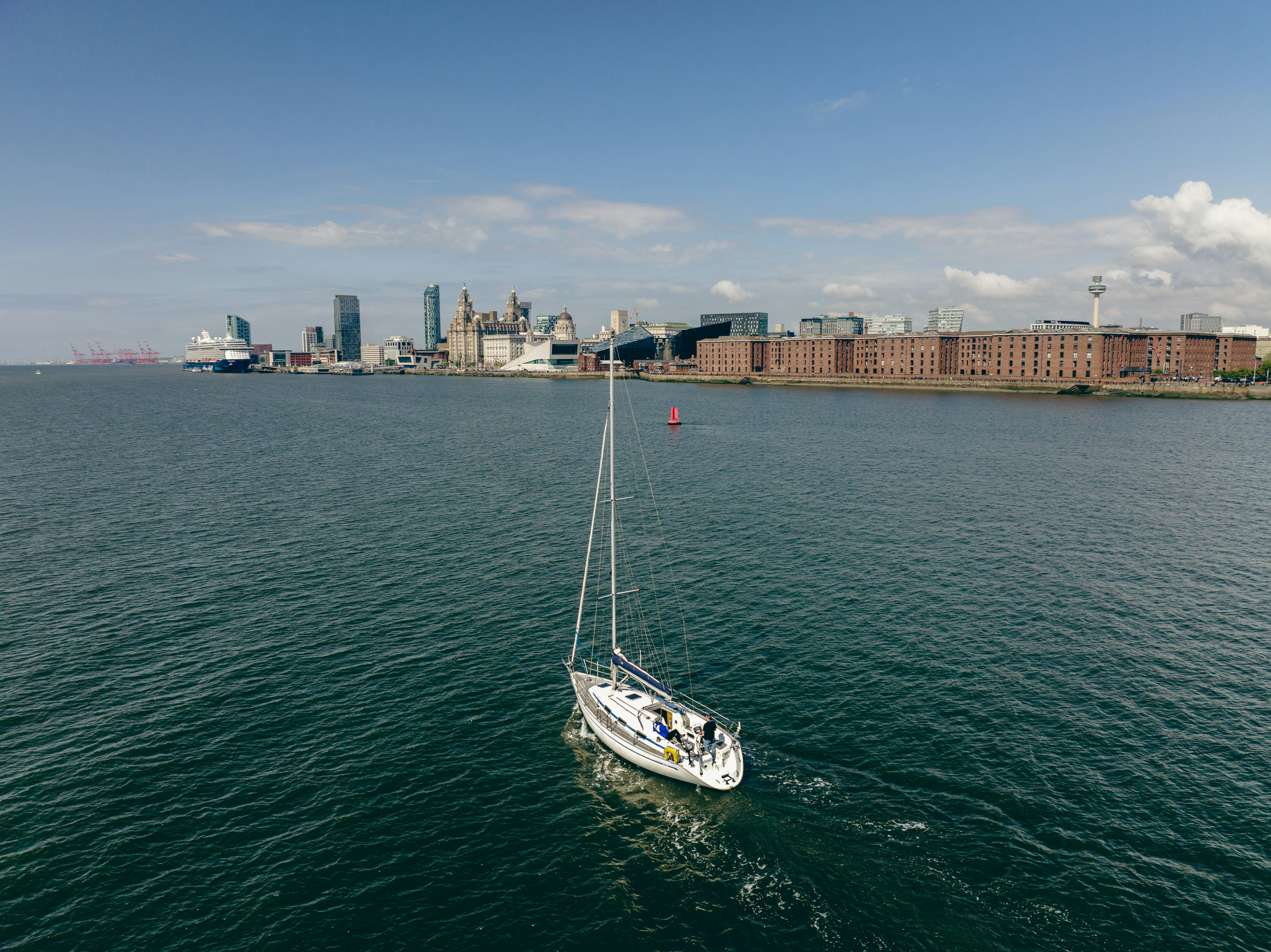 A sailboat sailing in the water near a city photo – Free River mersey ...