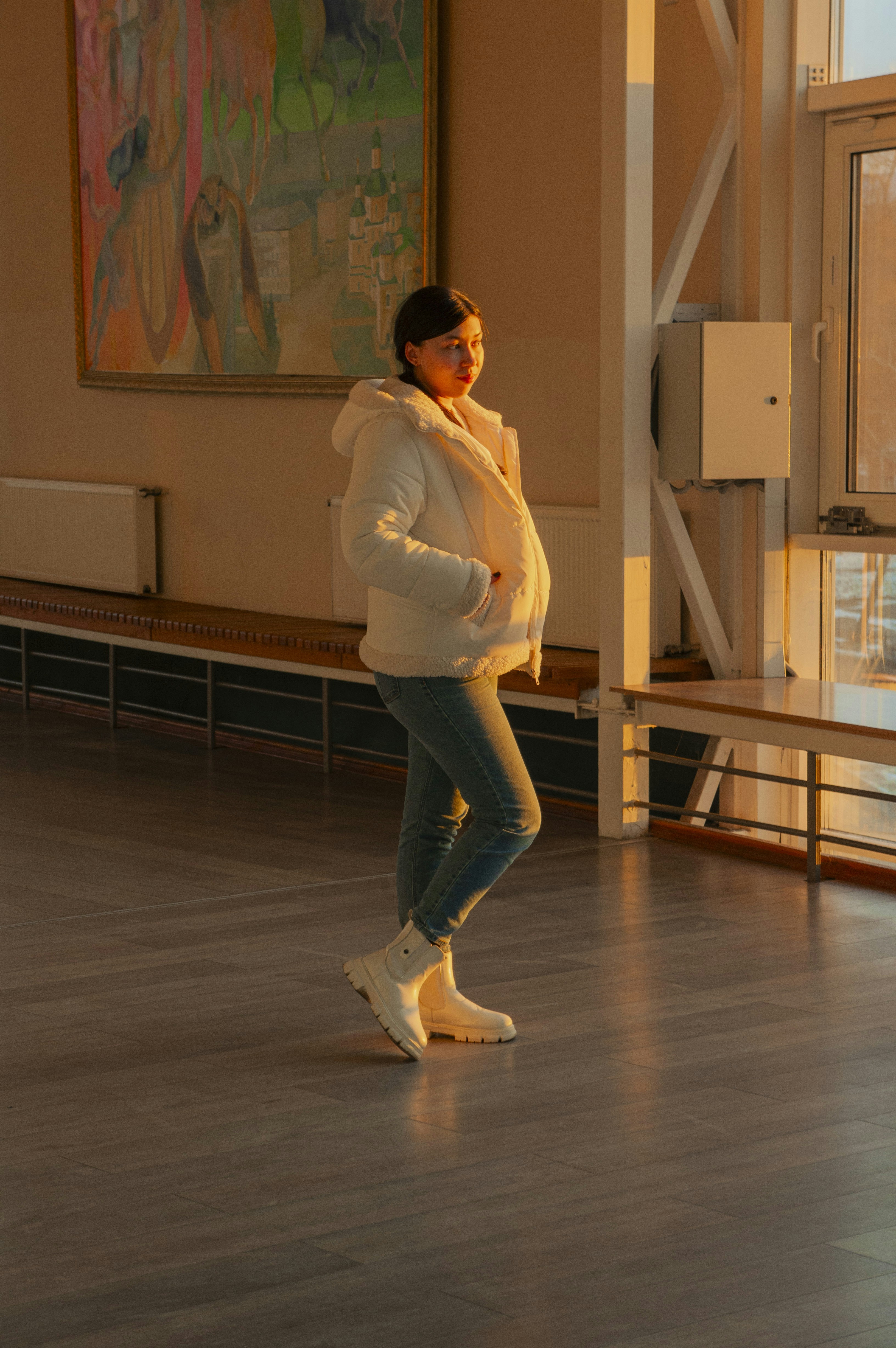 Amber-tinged Stillness: Woman in a White Puffer in a Quiet Hall